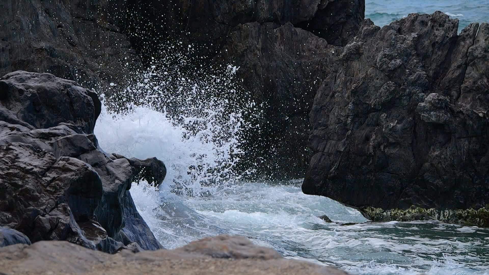 near the beach, sea waves wash over the rocks with big splashes, in ...