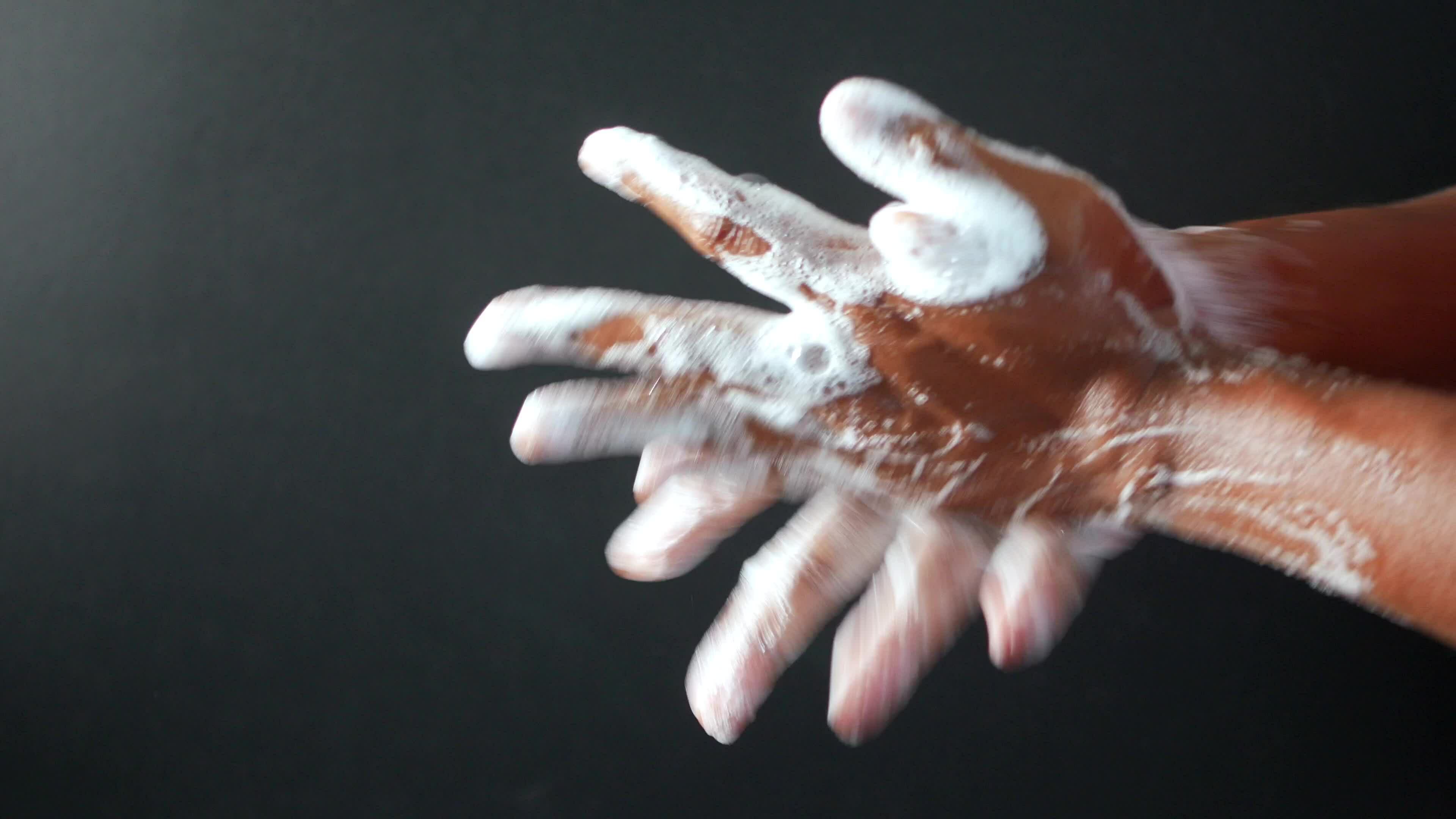 young man washing hands with soap warm water against black background ...