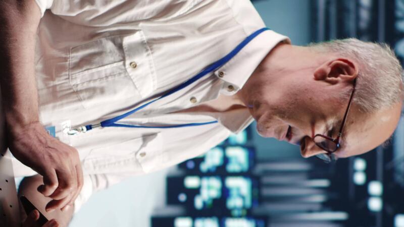 Vertical video IT solutions expert in data center environment, solving tasks on tablet while ...