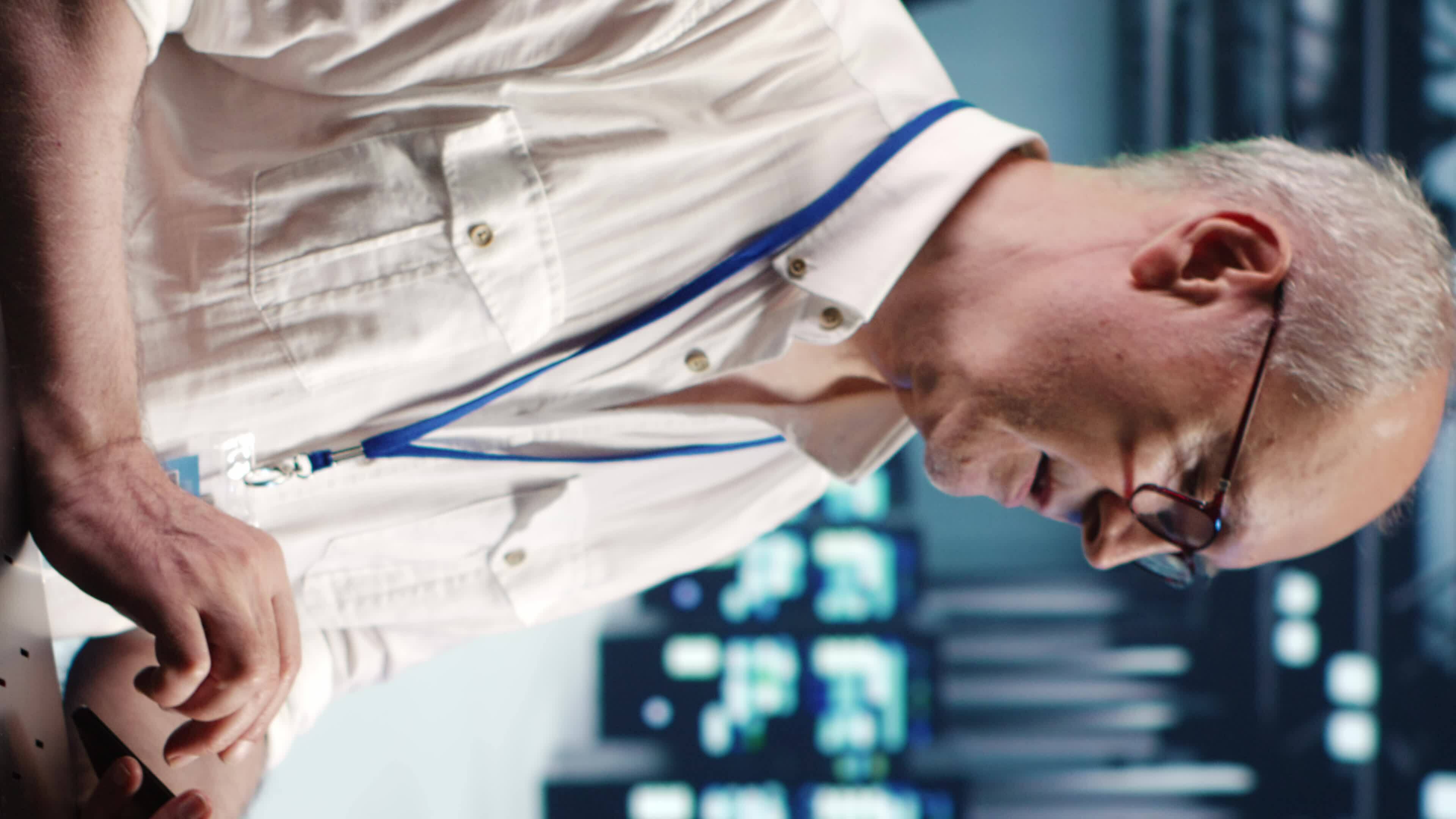 Vertical video IT solutions expert in data center environment, solving tasks on tablet while ...