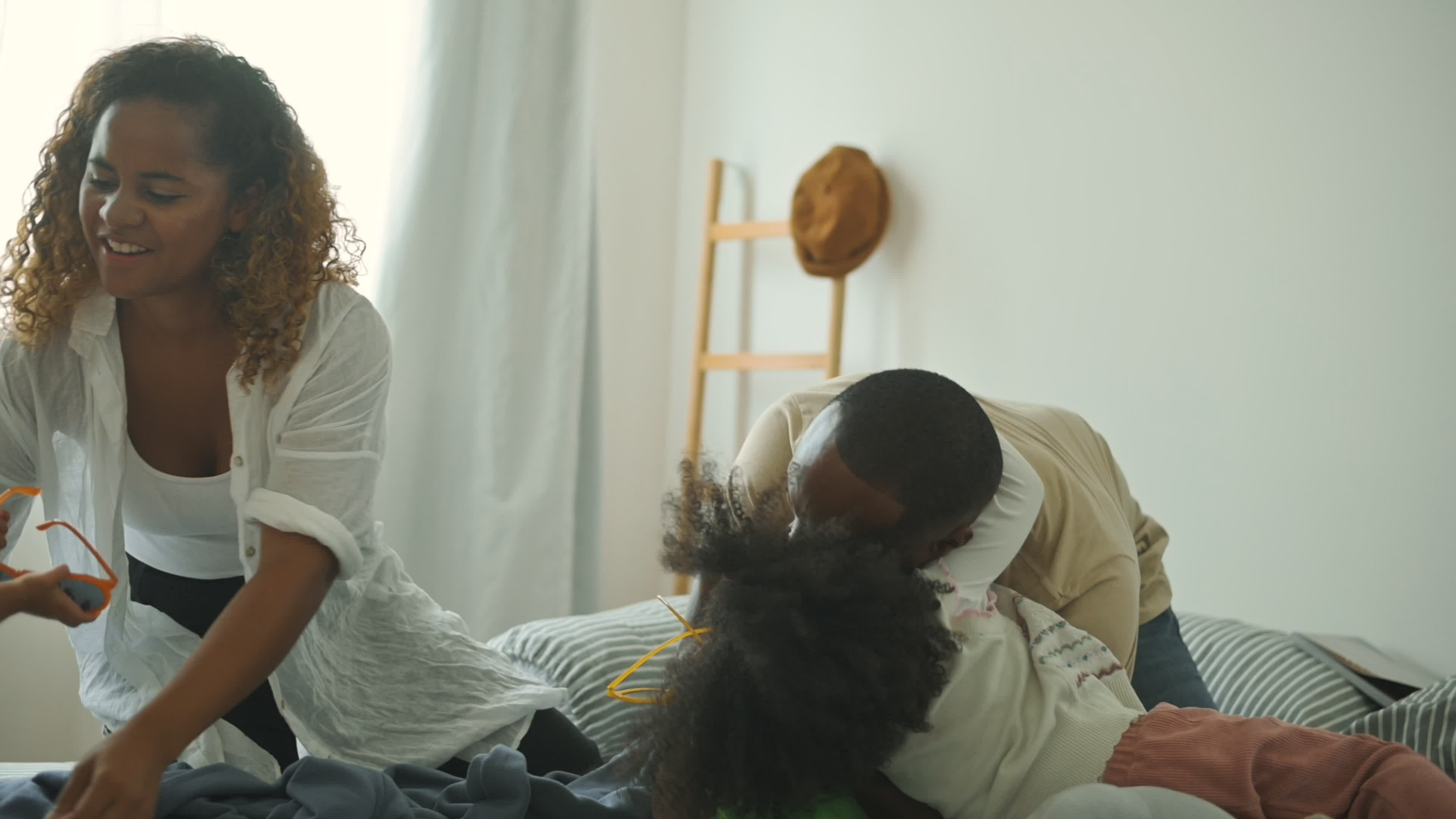 Happy African American Parents with little daughters playing on the bed in bedroom at home ...