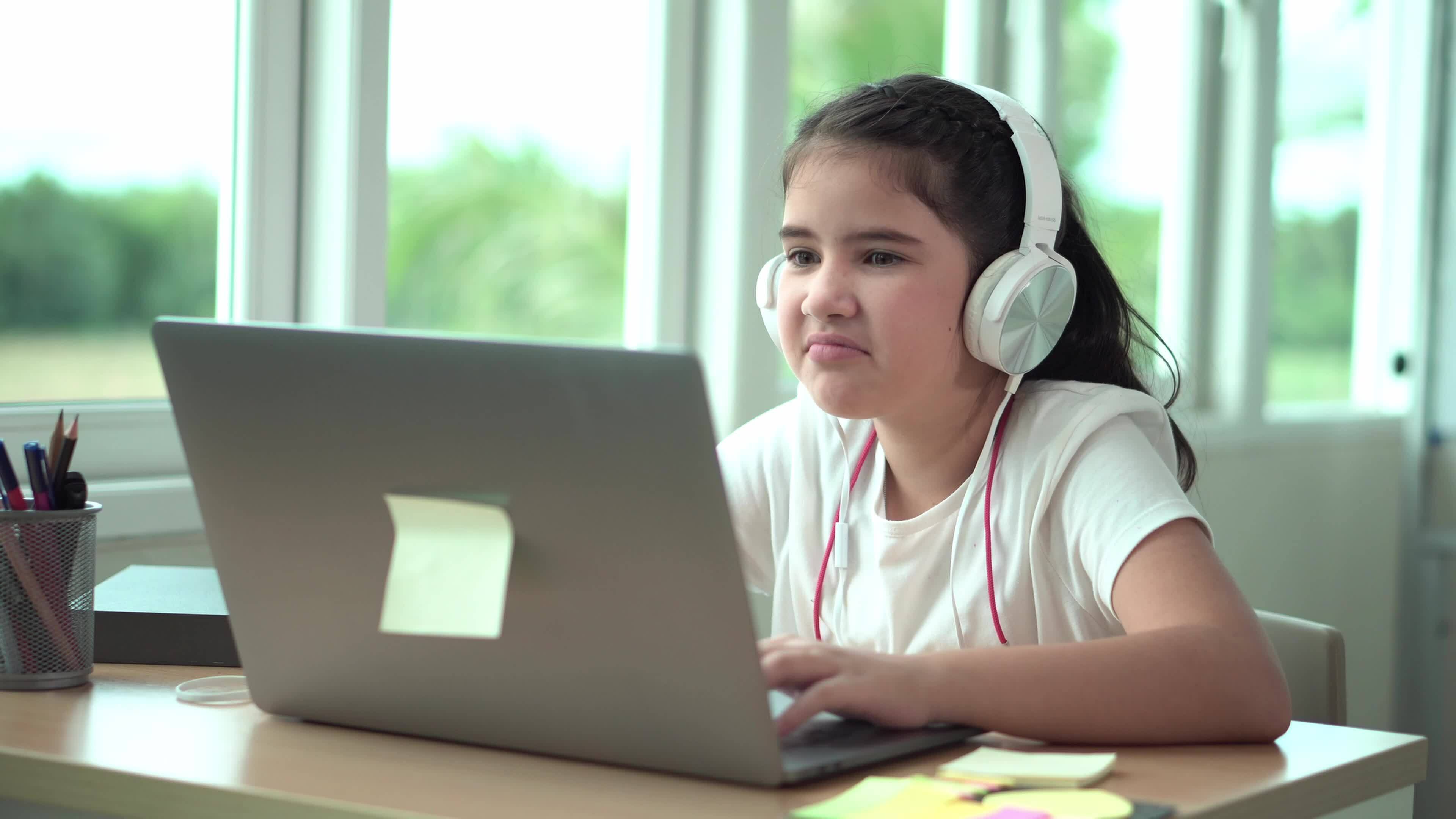 Kid girl smile learns lessons e-learning on computer notebook from home ...