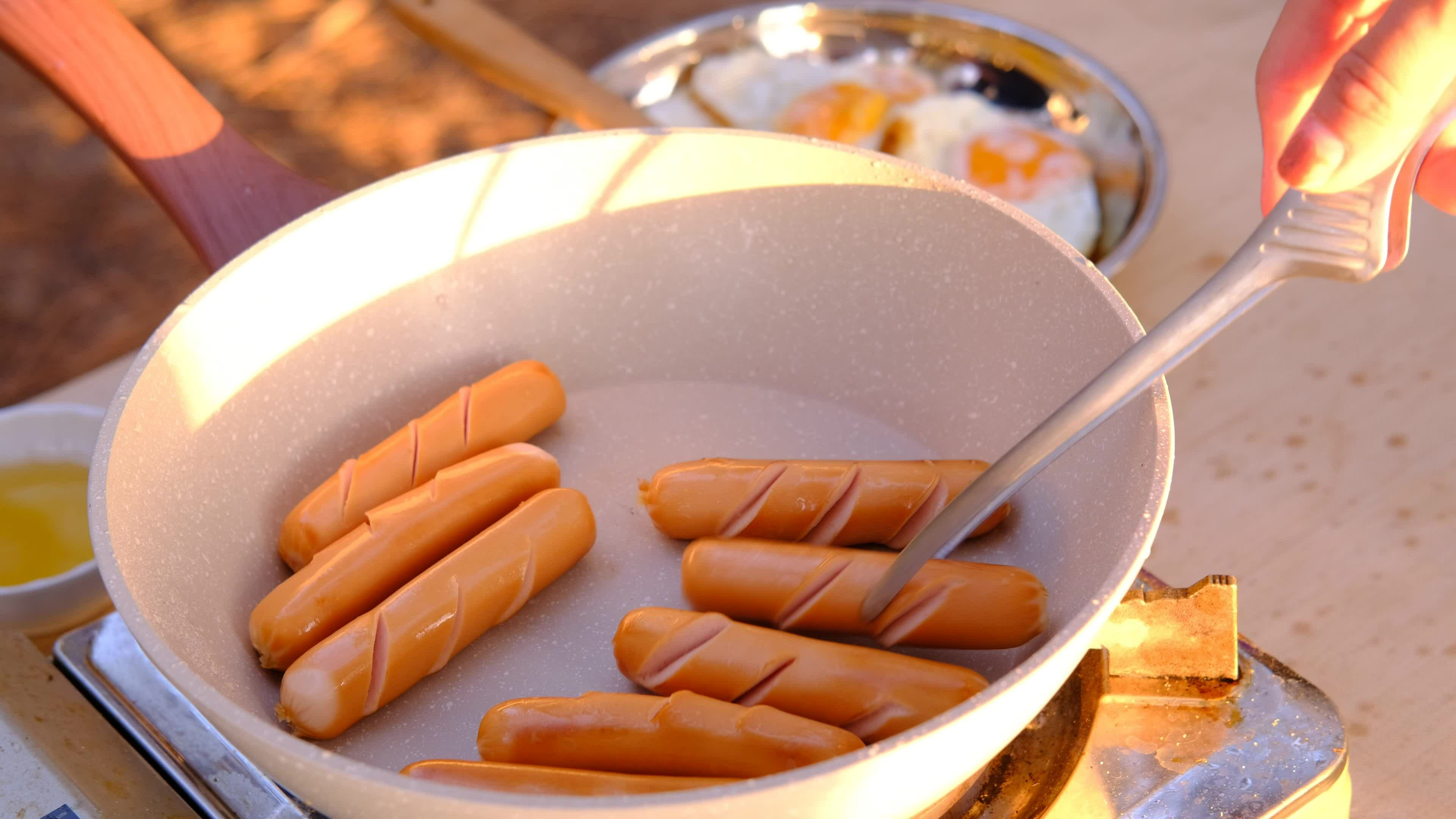 A Womans Hand Is Holding Sausages And Placing Them On A Plate While Going Camping To Relax