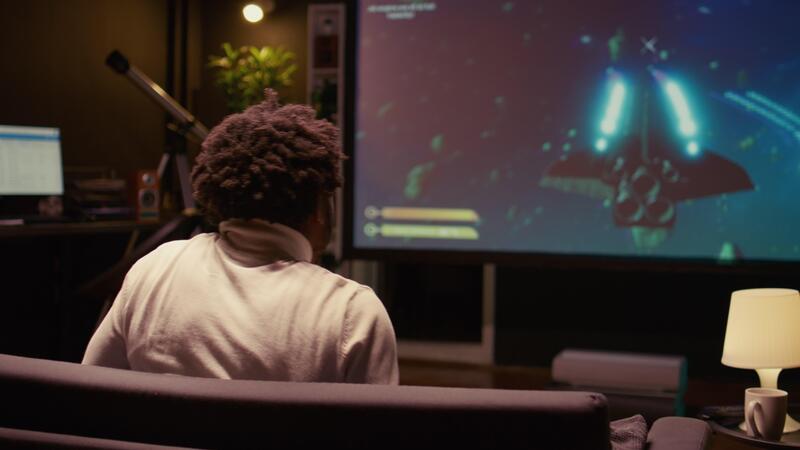 Bipoc Gamer Focused On Defeating Enemies In Classic Arcade Space Shooter Videogame On Ultrawide