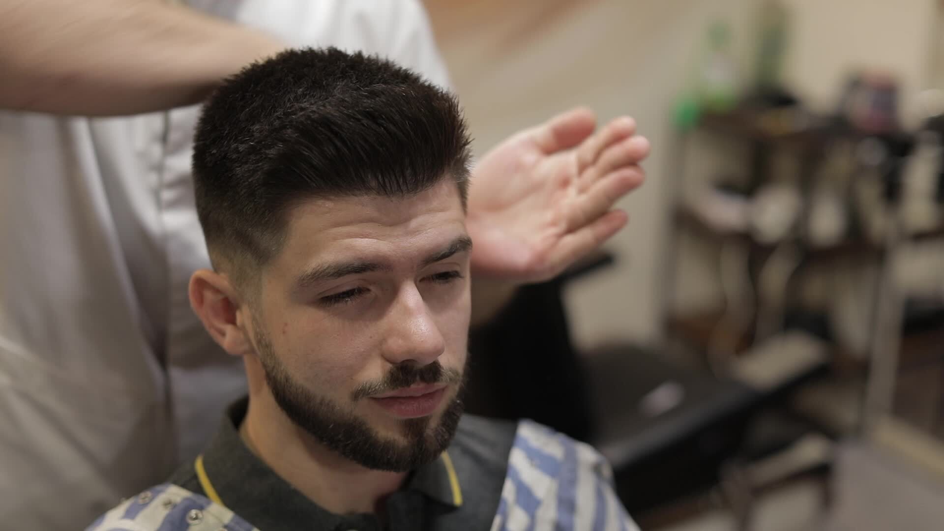 Client with black beard during hair cut in barber shop. Groom ...