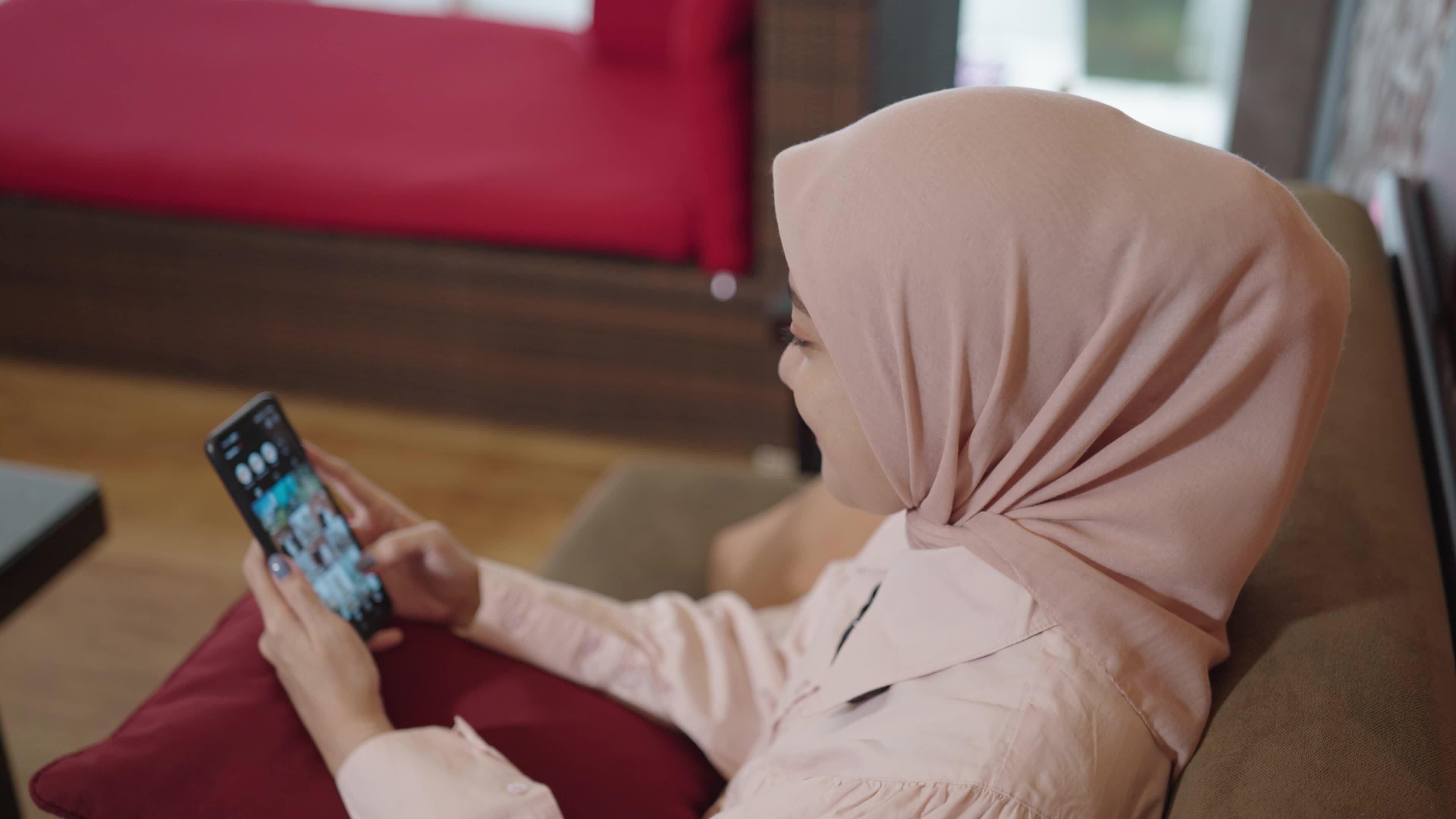 Modern Muslim Woman on Hijab Southeast Asian - Smiling, Looking and Scrolling her Smartphone ...