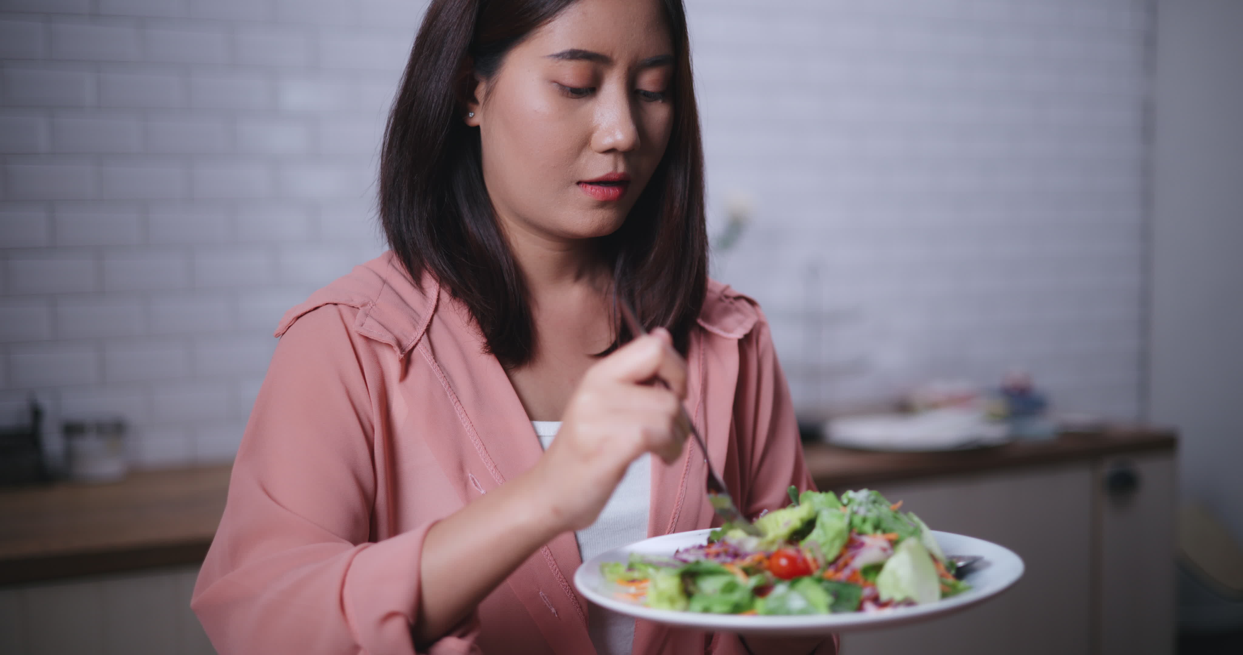Footage Of Young Asian Woman Eating Vegetable Salad In Kitchen At Home