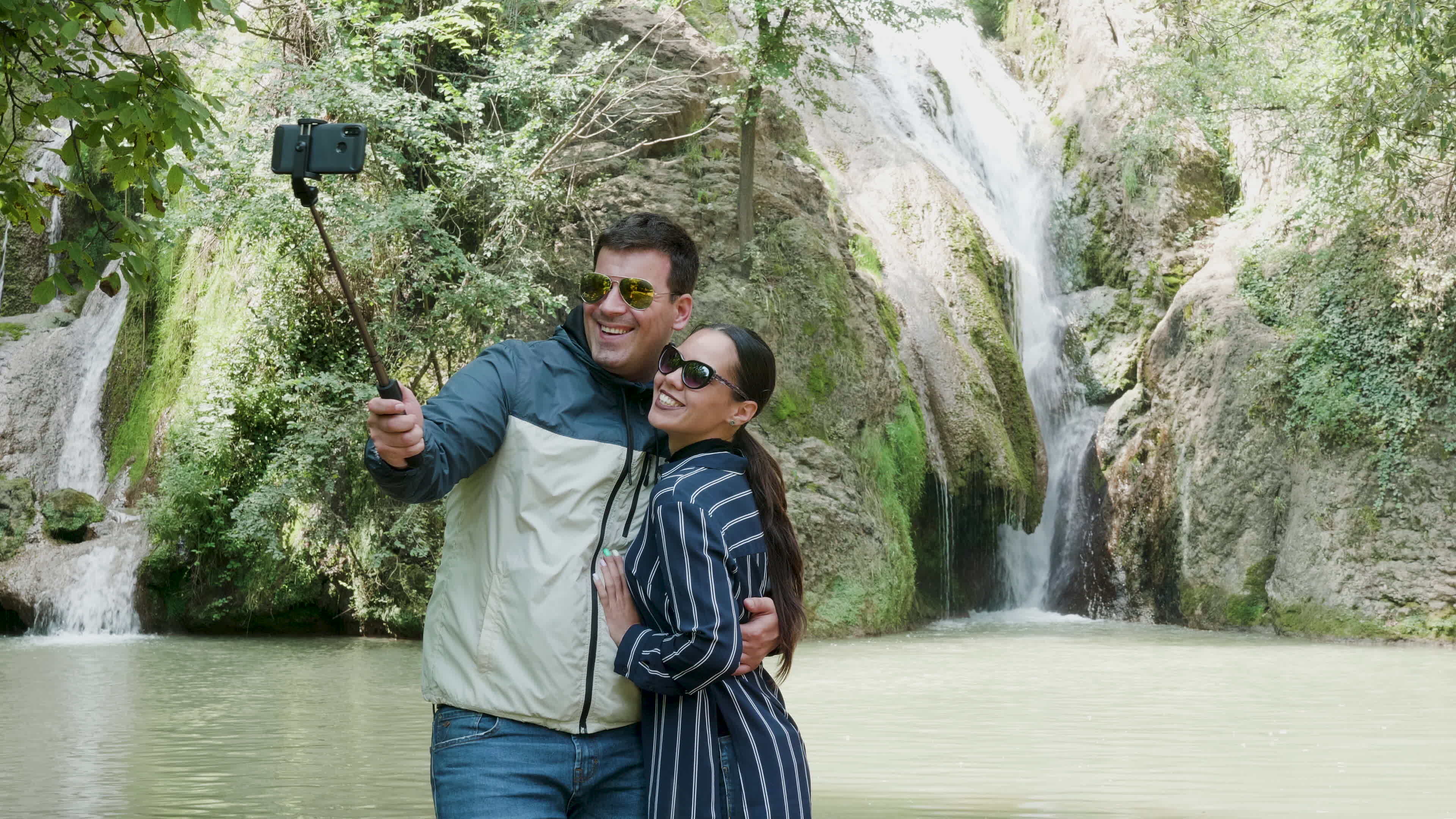 Gorgeous tourist couple takes a selfie near a waterfall. Tourism and ...