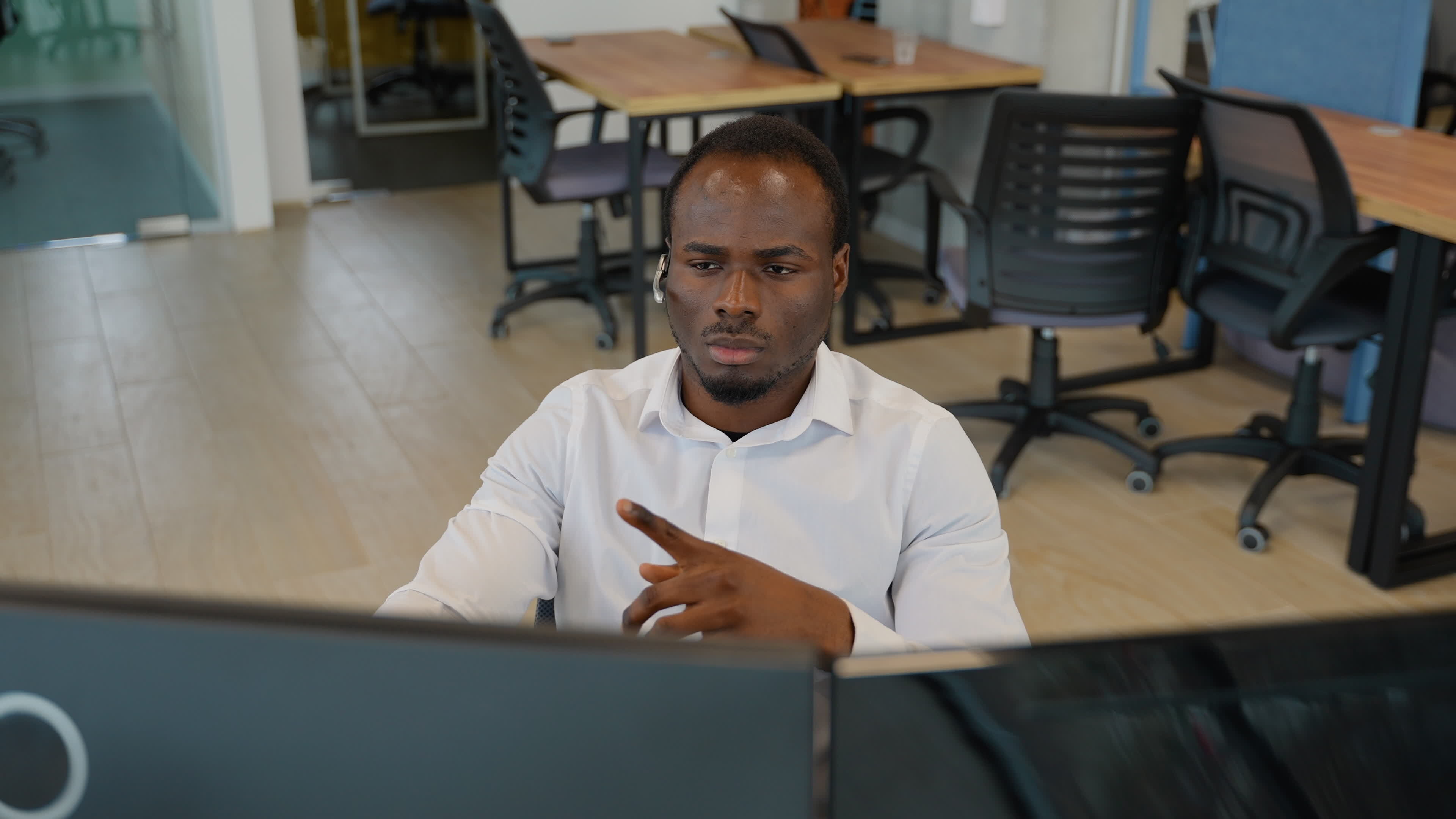 Concentrated african crypto trader sitting in front of computers, making professional analysis ...
