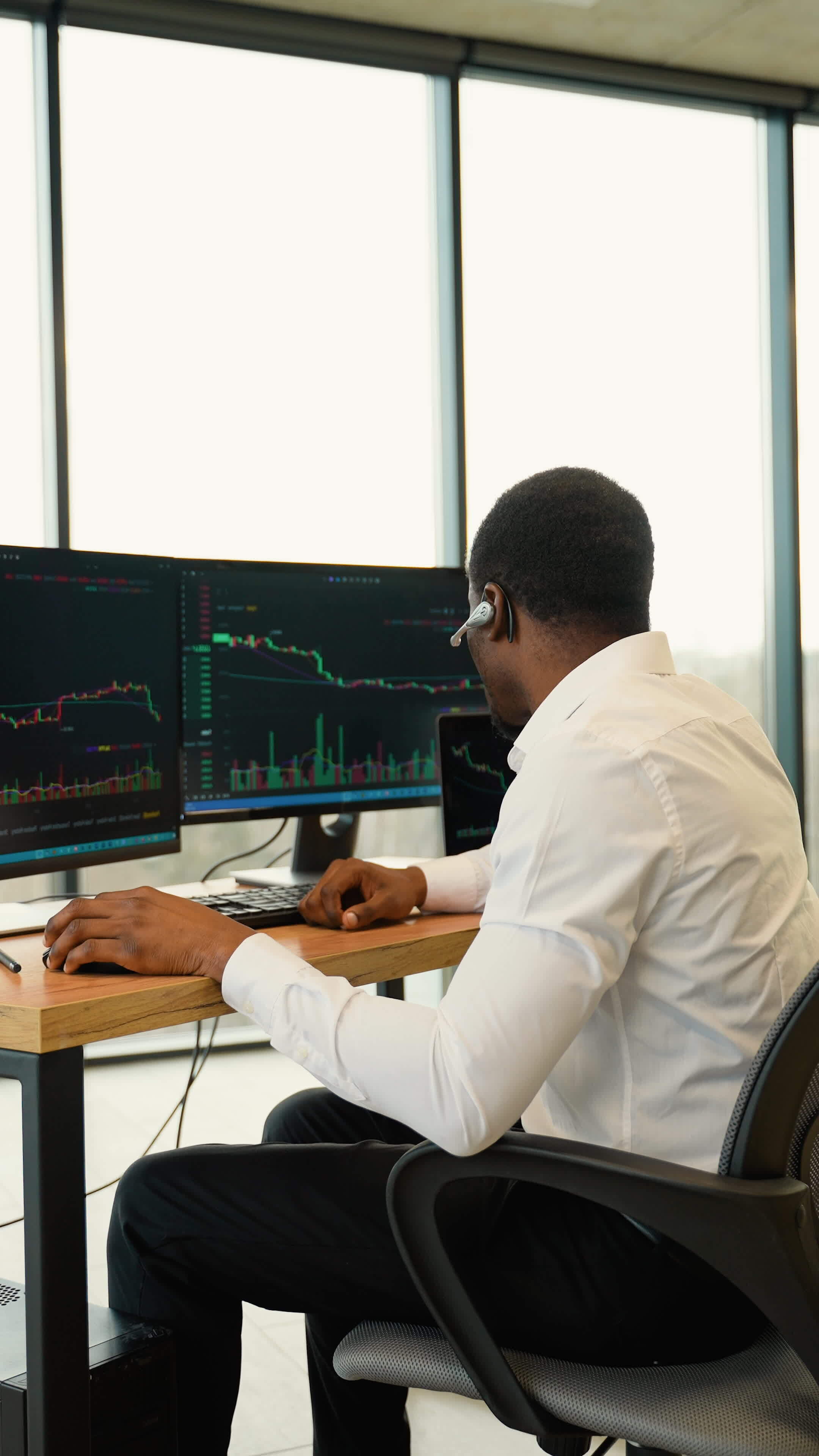 Concentrated african crypto trader sitting in front of computers ...