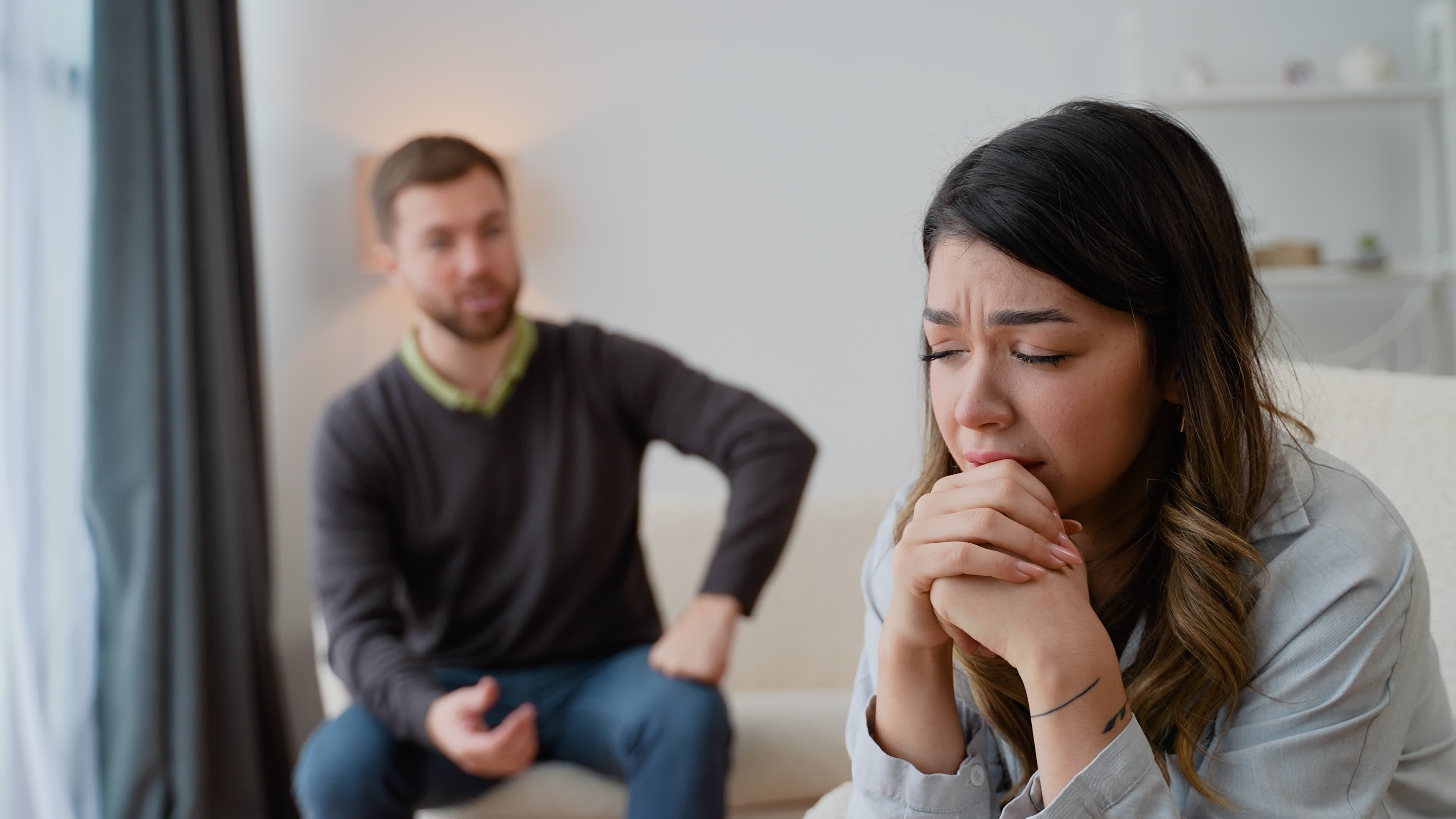 Tired stressed woman crying sitting on bed on blurred background of ...