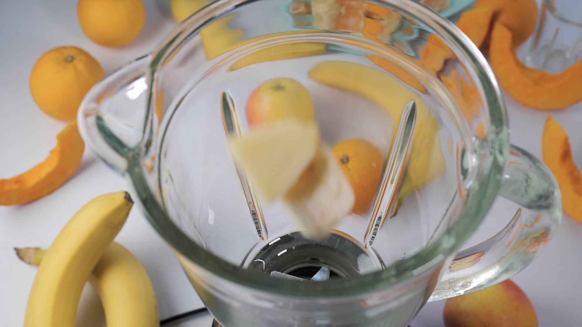 Fruit falling into a blender, super slow motion. Orange, banana, apple in a blender, top view ...