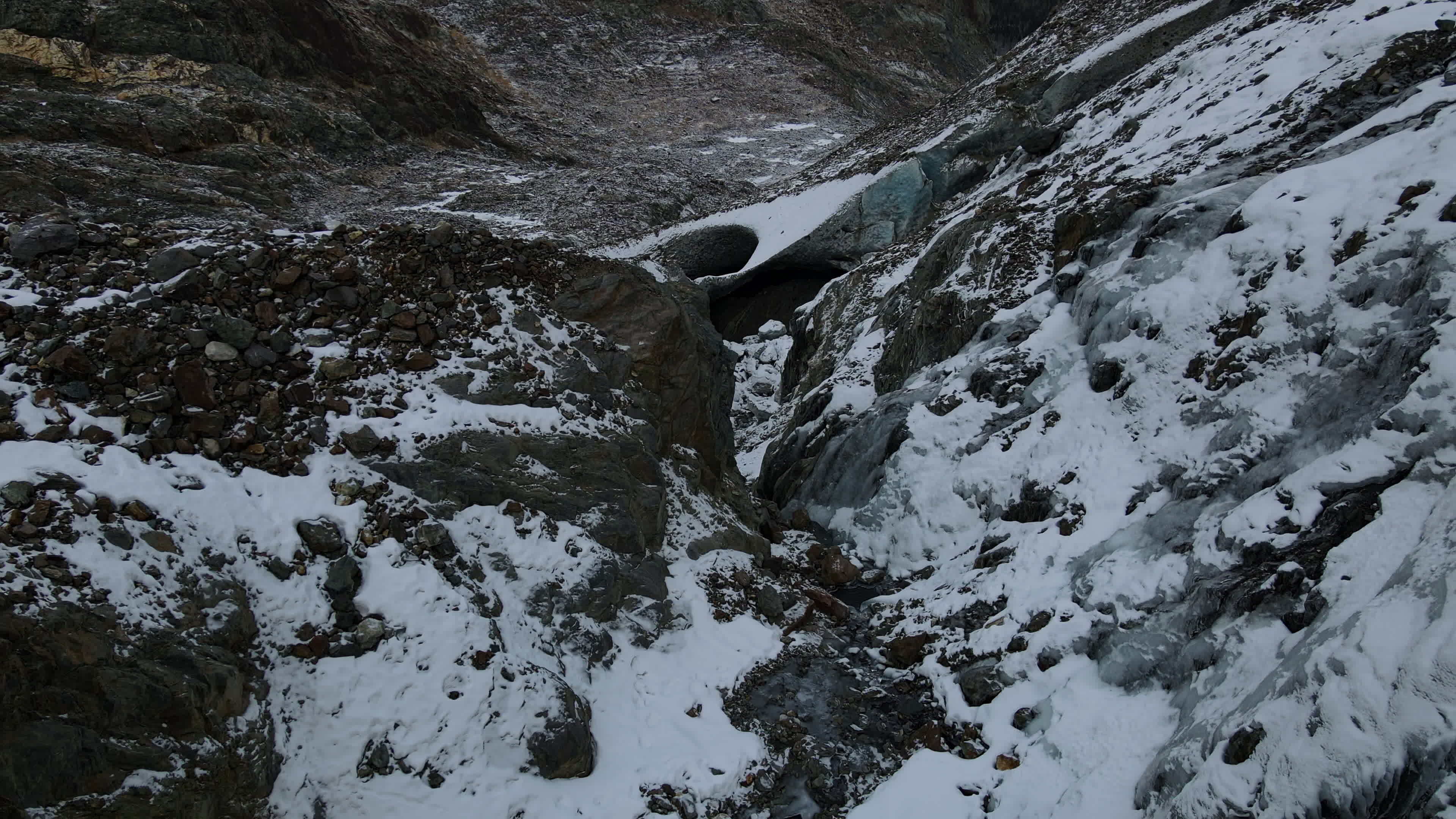 Through snowy weather camera sweeps over rocky terrain aerial top view ...