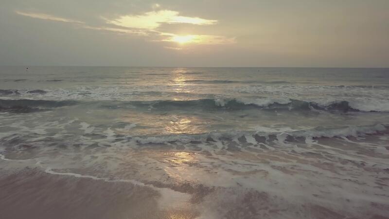 Sunset on the beach - Tranquil idyllic scene of a golden sunset over the sea, waves slowly ...