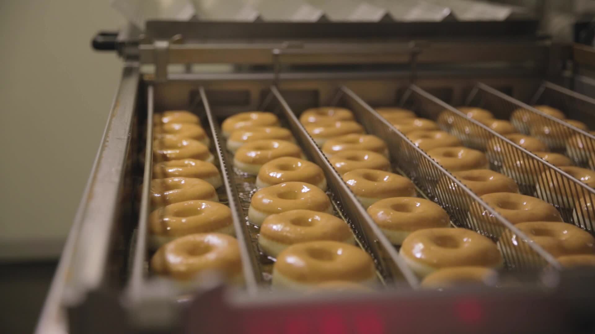 Procedure of making donuts in a small town donut bakery - donuts frying in a deep fryer. Scene ...