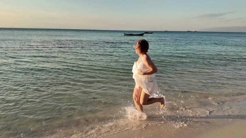 Joyful Woman Running in Ocean Waves at sunset 38598700 Stock Video at Vecteezy