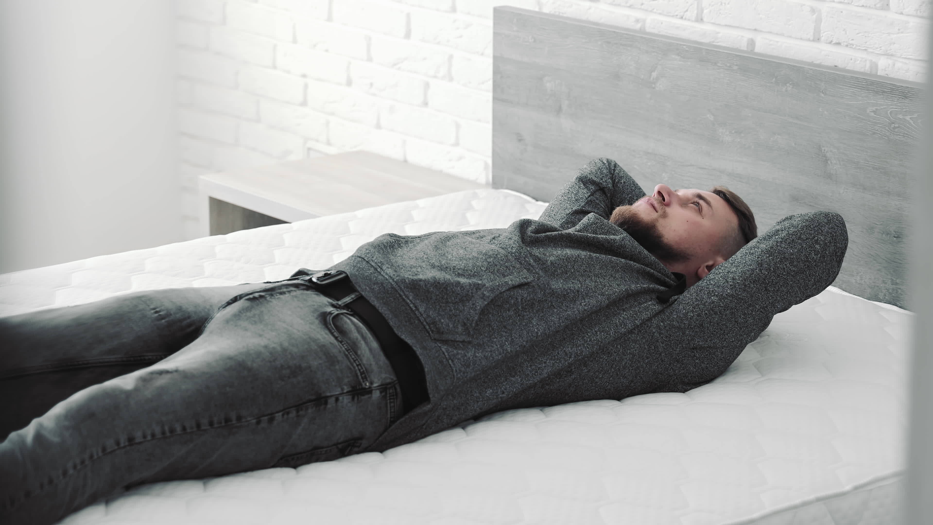 Man Lying Down in Thought, Young man resting on a bed, gazing upwards in a moment of relaxation ...