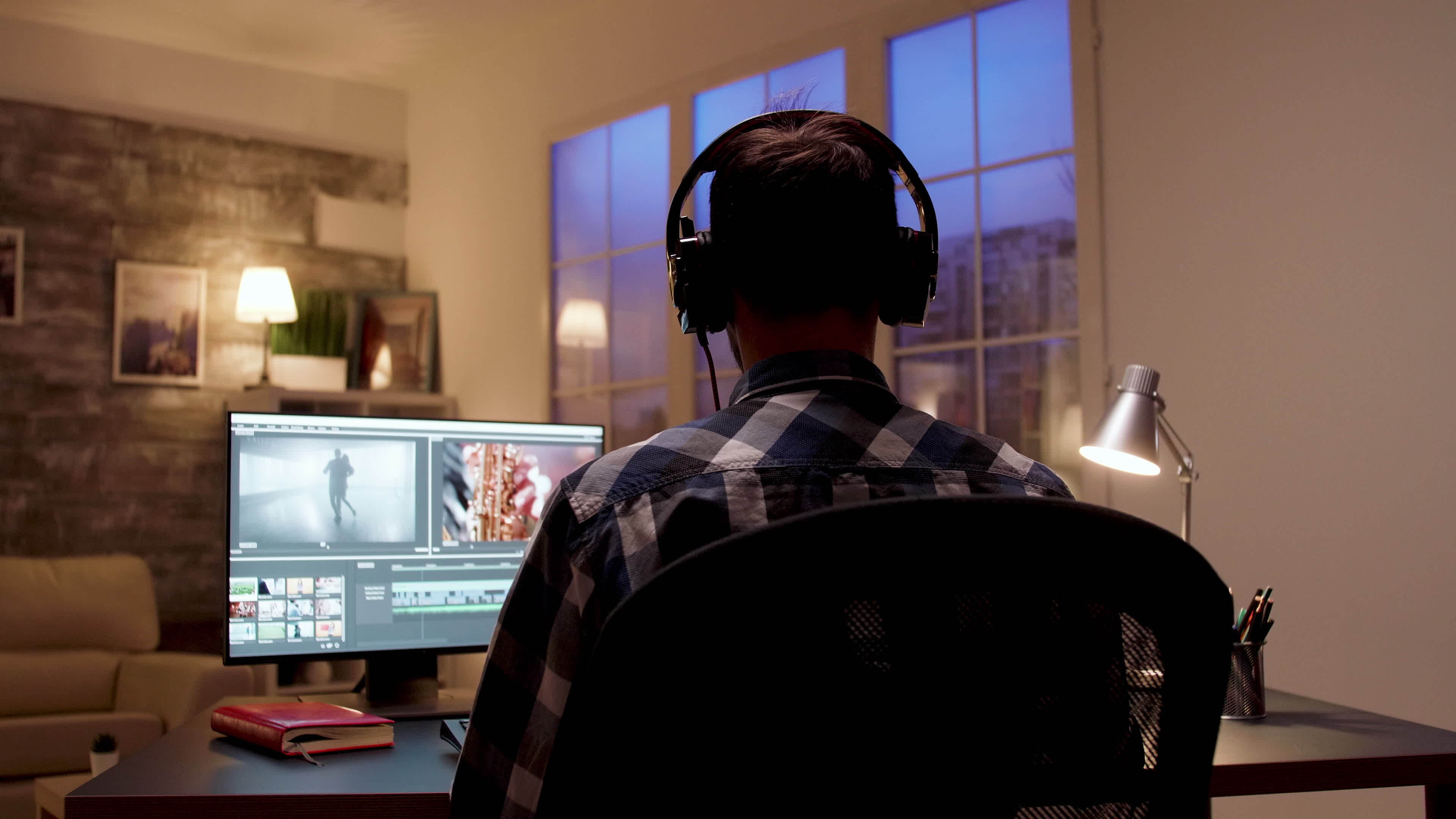 Back View Of Videographer With Headset Working Late At Night On A New Project Editor Using