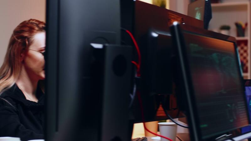 Girl hacker looking at super computer with multiple monitors while writing a malware. 40291888 ...