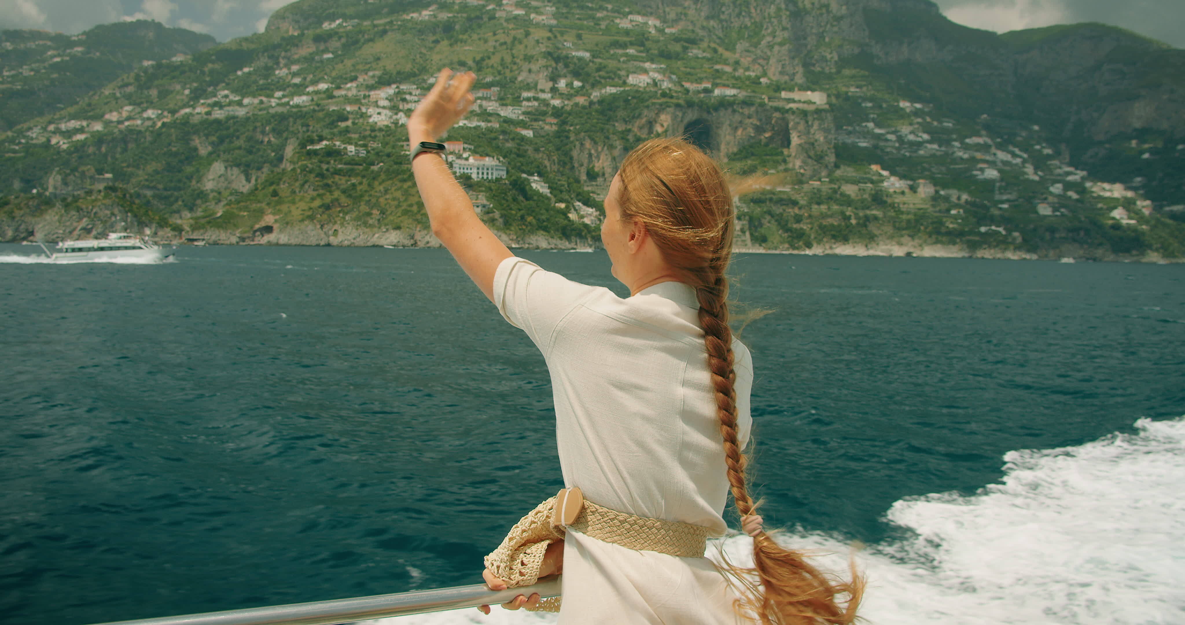 A woman waves to the yacht from a boat while traveling on summer sea ...
