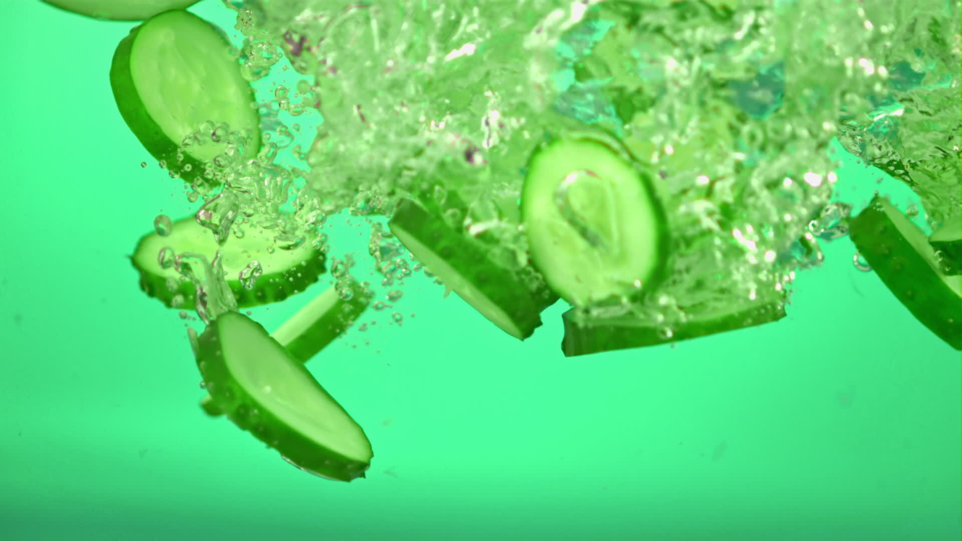 Super slow motion pieces of cucumber under water with air bubbles. On a green background. Filmed ...