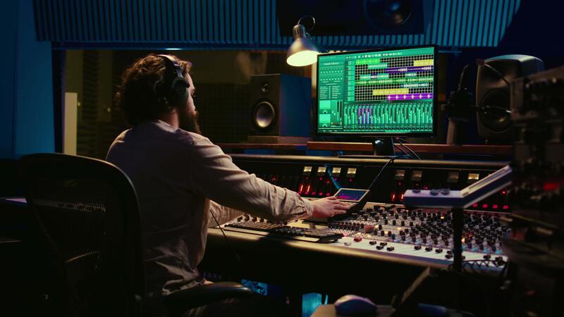 Using audio editing software, sound producer creates tunes and handling ...