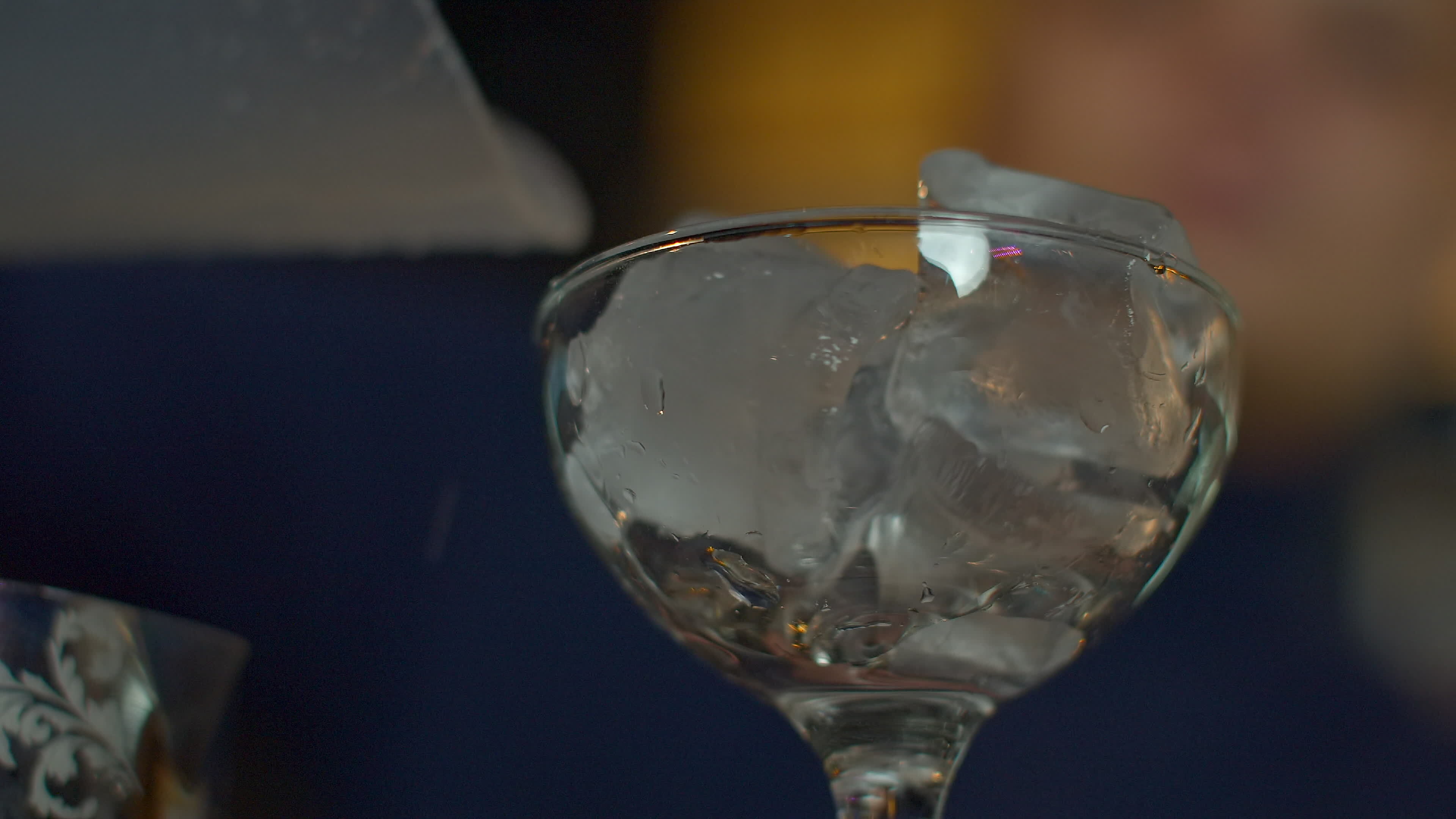 Close up of bartender putting large cubes of ice nto the empty vintage glass. Media ...
