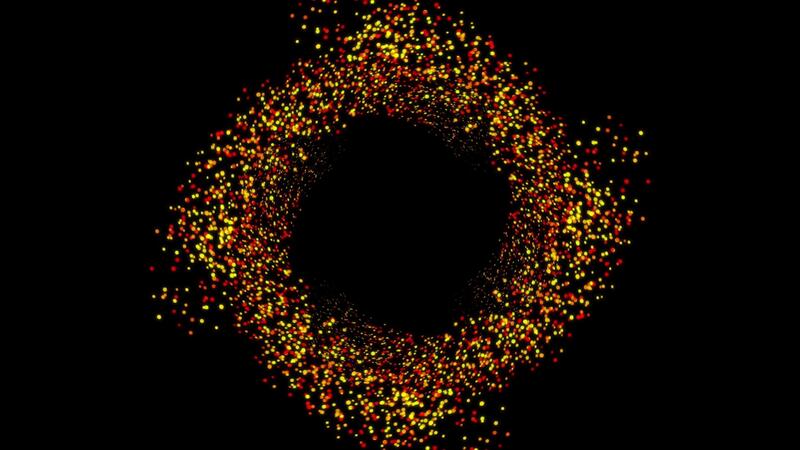 Small particles of red and yellow colors rotate on a black background forming a circle ...