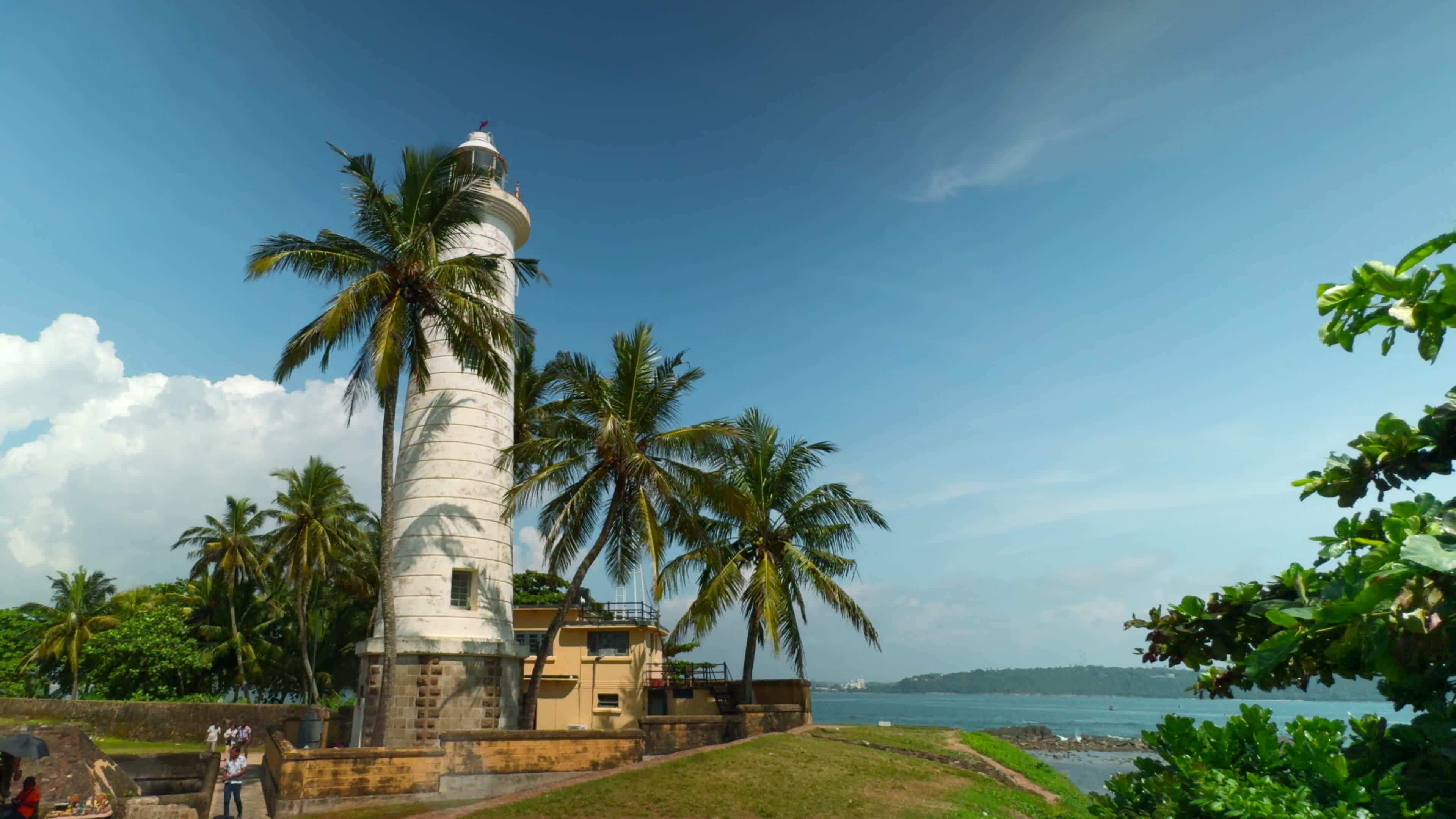 Beautiful lighthouse with palm trees on shore of tropical bay. Action ...