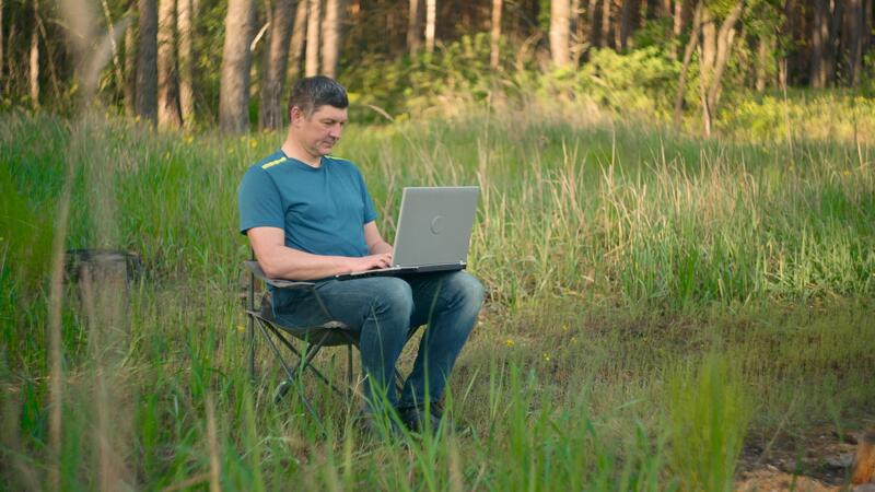 Crazy programmer working on laptop in summer forest At The Sunny Day ...
