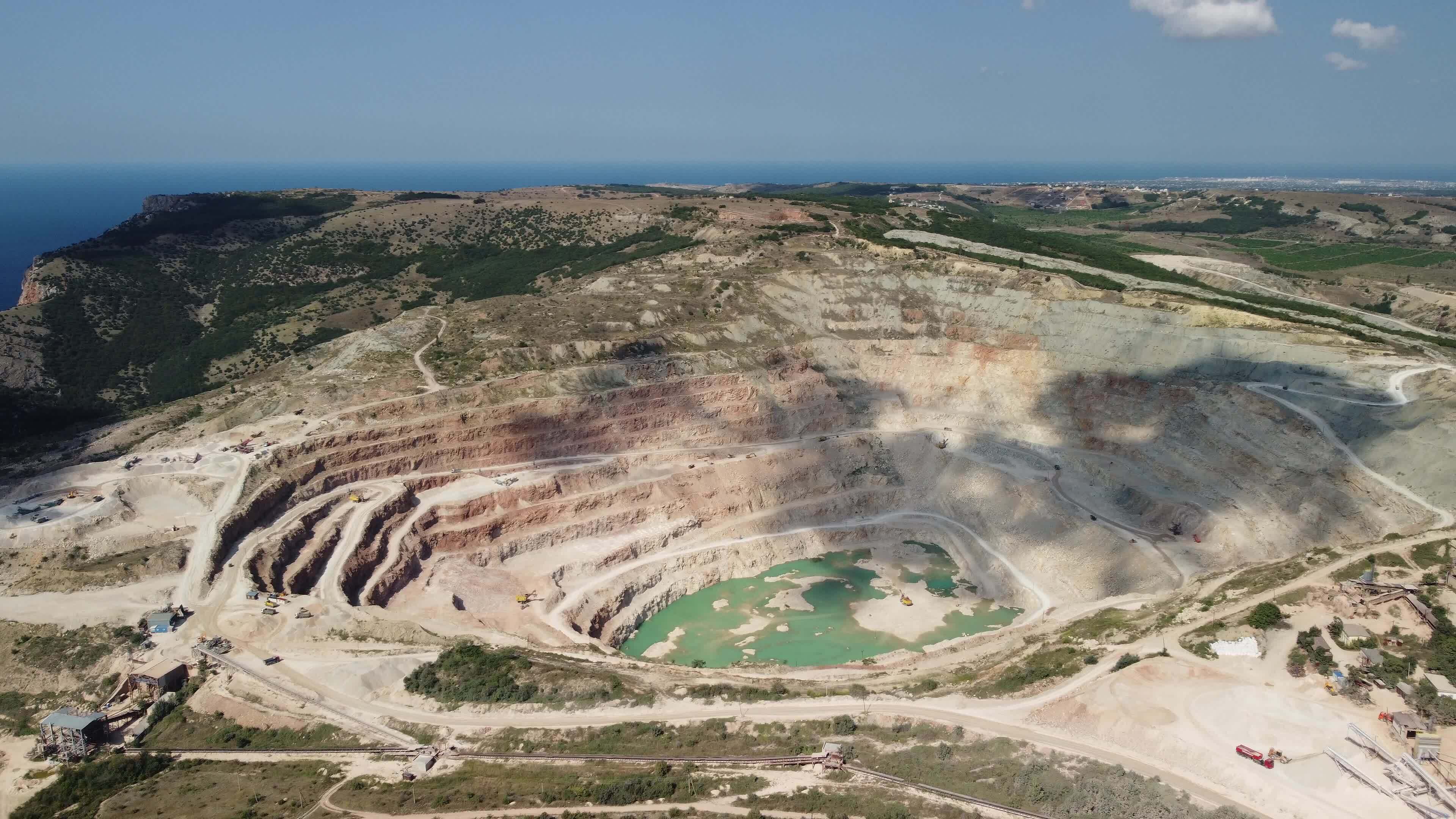 Aerial view industrial of opencast mining quarry with lots of machinery at work - extracting ...