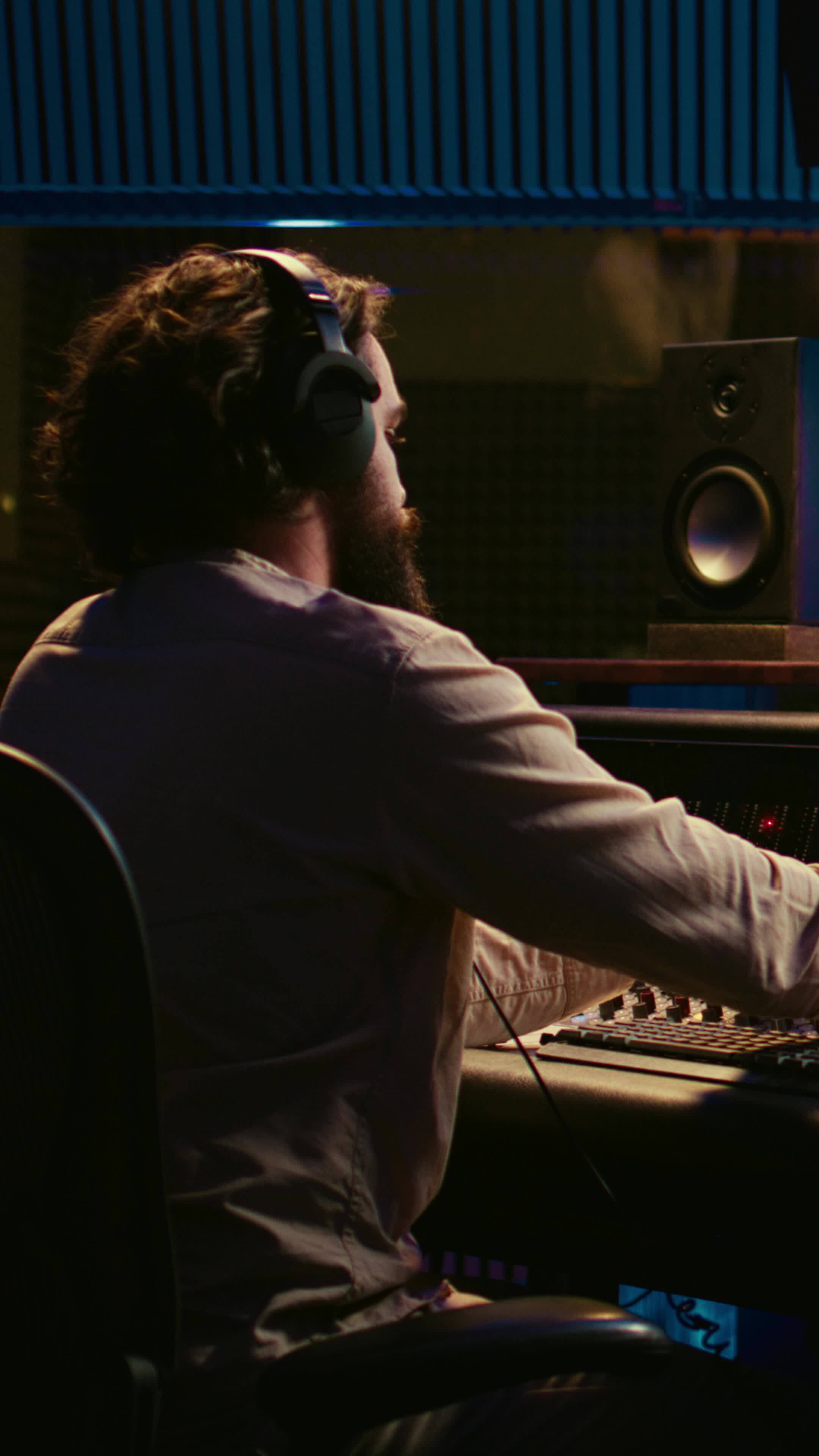 Vertical Using audio editing software, sound producer creates tunes and ...