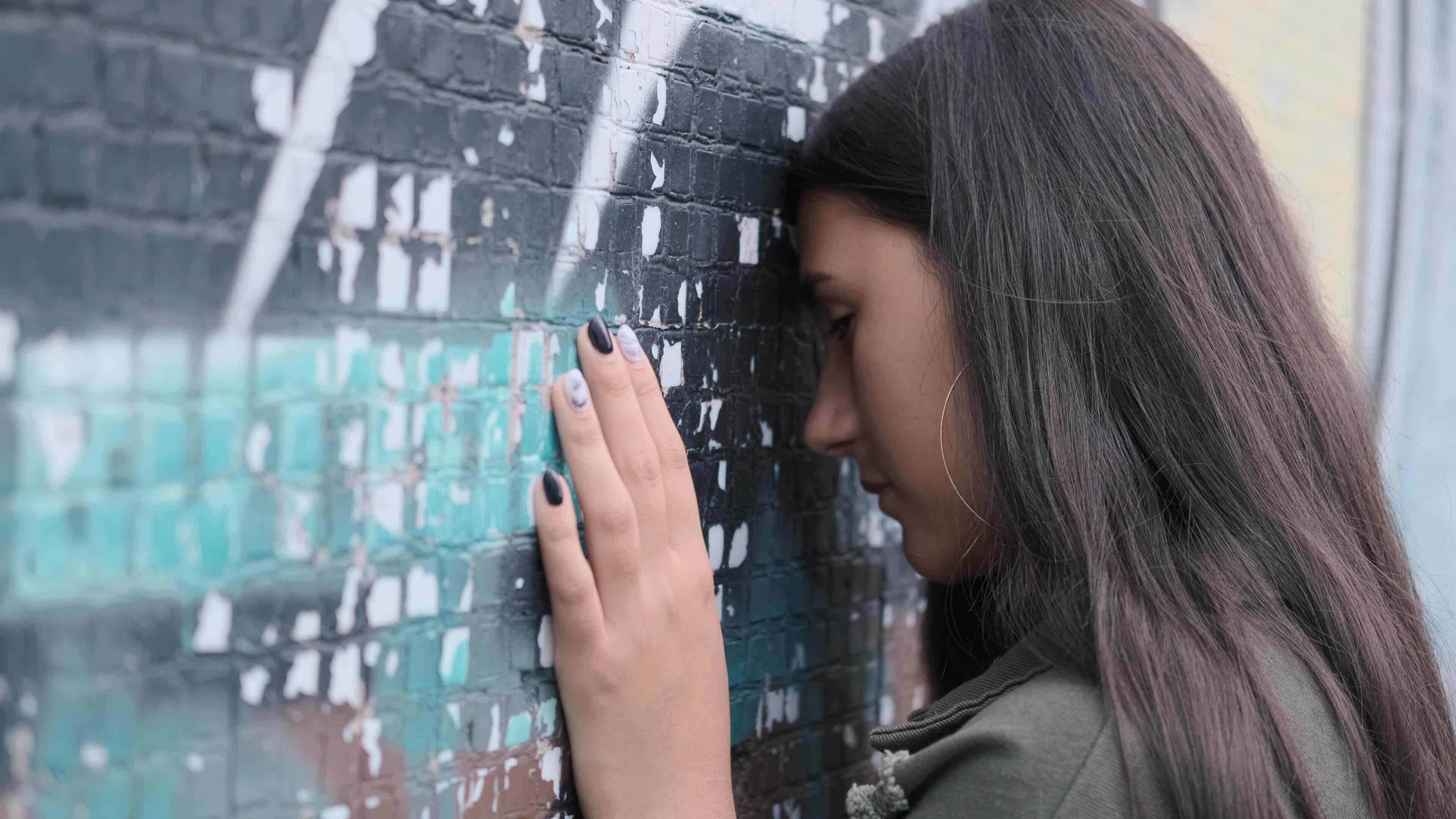 sad young brunette girl with long hair and brown eyes is standing with ...