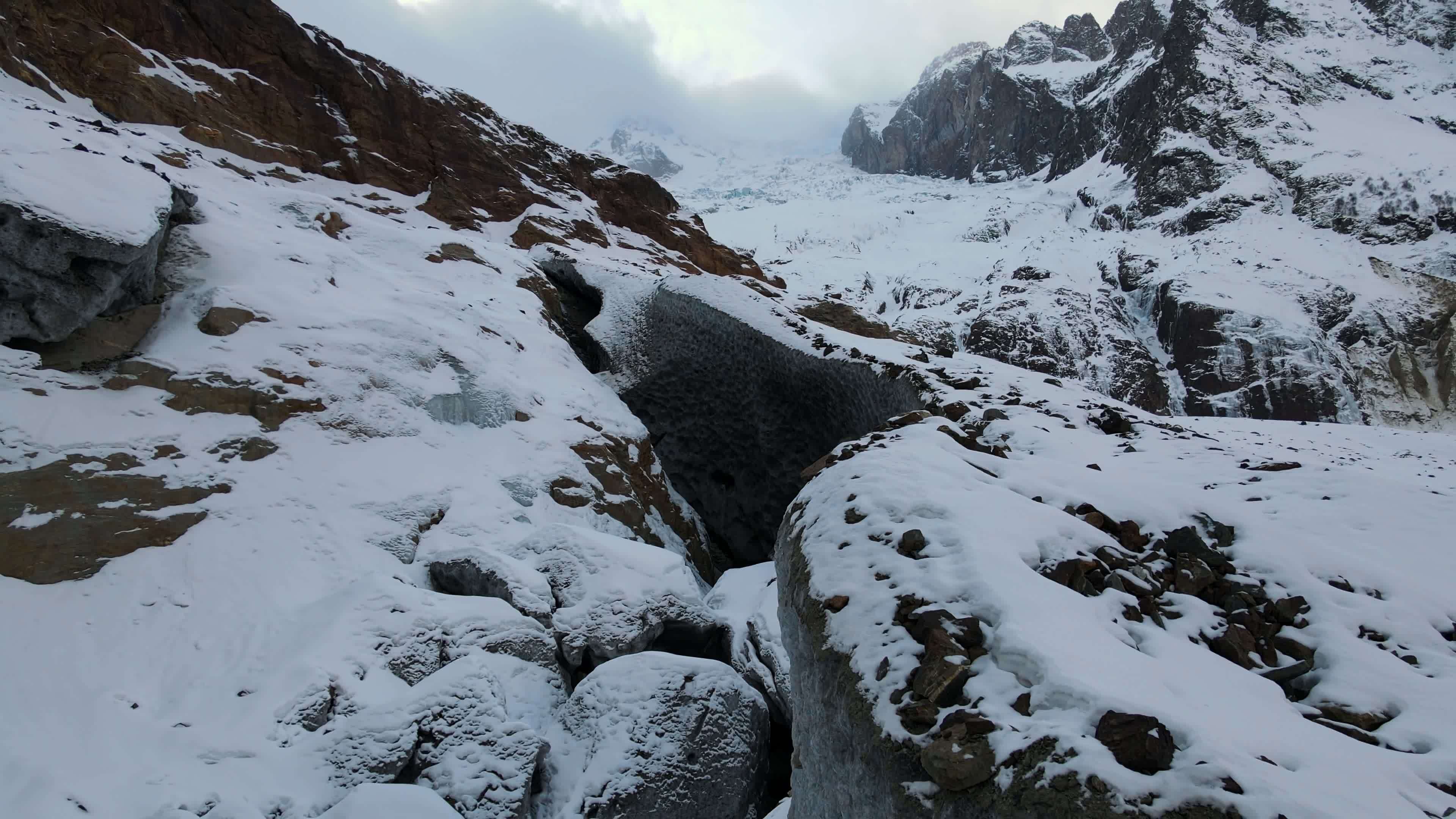Through snowy weather camera sweeps over rocky terrain aerial top view ...