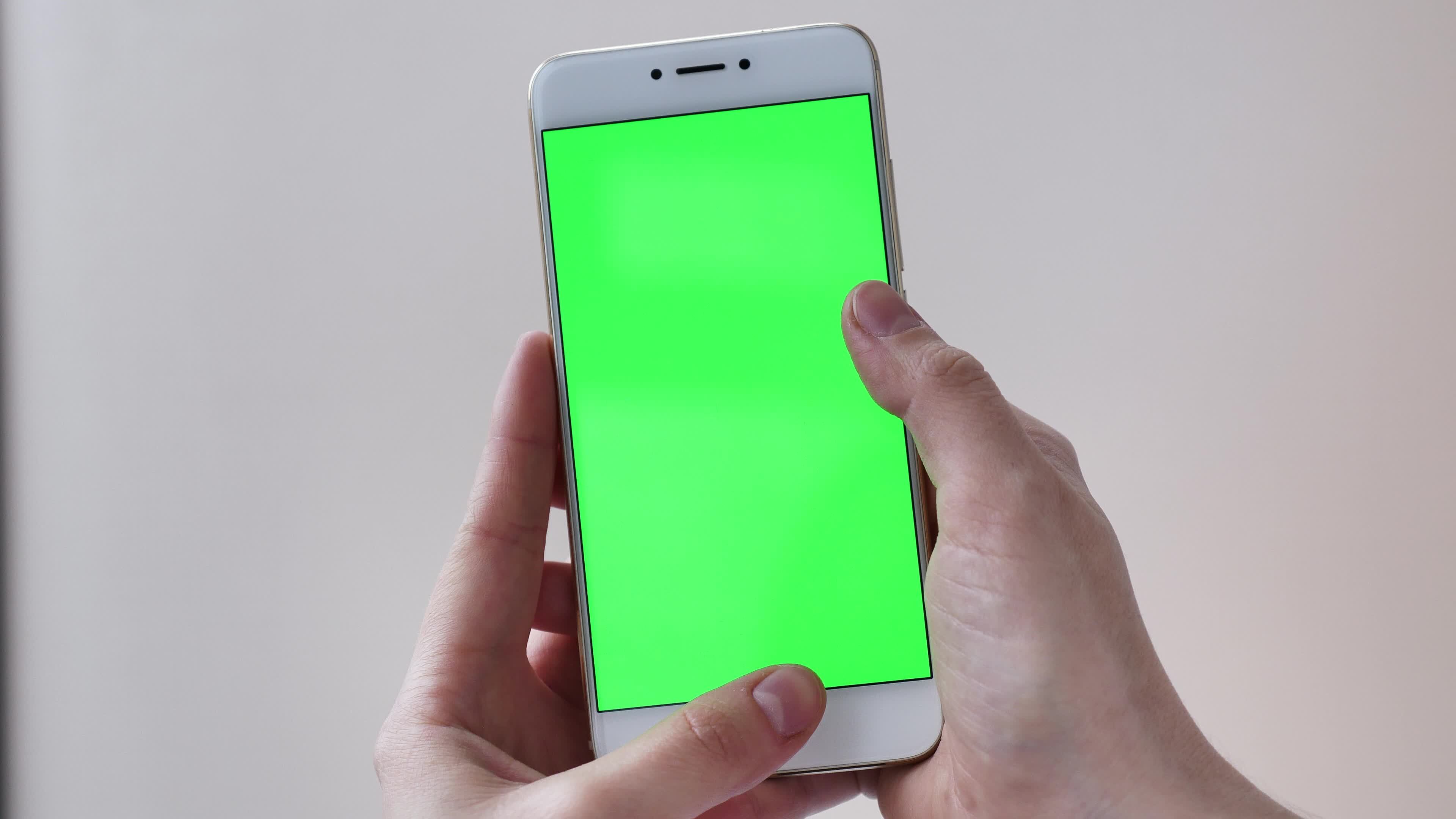 POV scrolling phone with green screen on white isolated background close-up in female hands ...