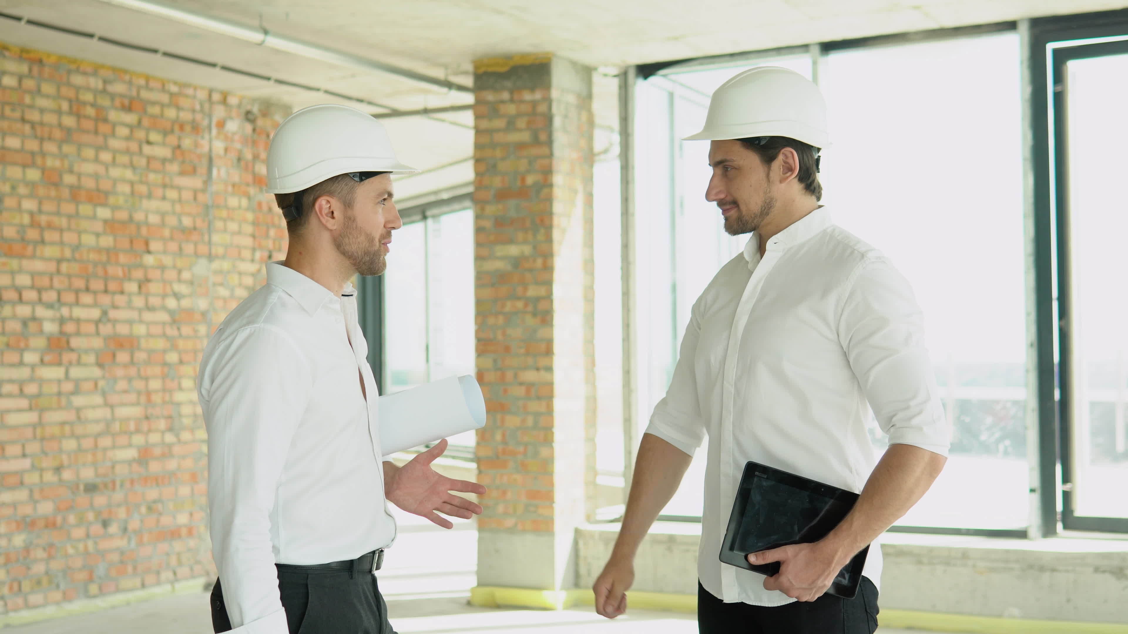 Friendly handshake of two builders at a construction site. Close up of ...