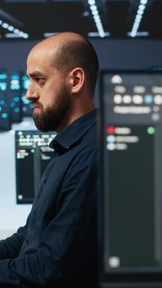 Vertical Software developer programming in high tech facility with server rows providing ...