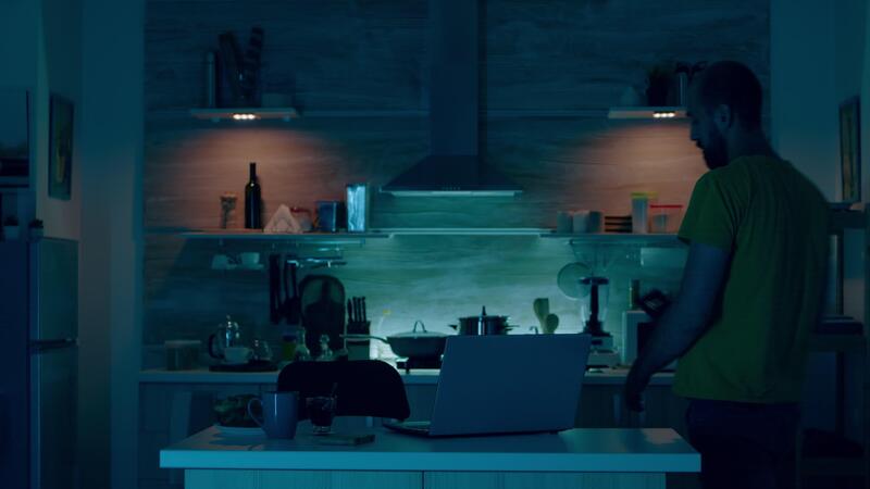 Young Person Coming In Kitchen Holding Mobile Giving Voice Command To Smart Home Application And