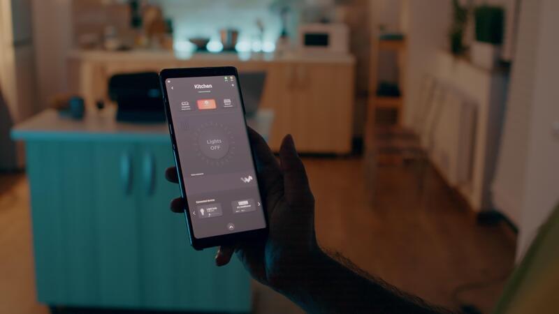 Person sitting in house with automation light system holding smartphone ...