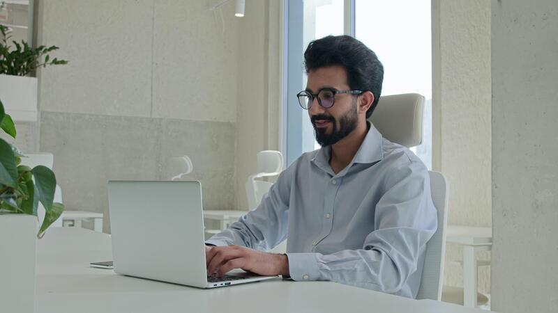 Arabian Indian muslim businessman ethnic man working with computer at corporate office cheerful ...