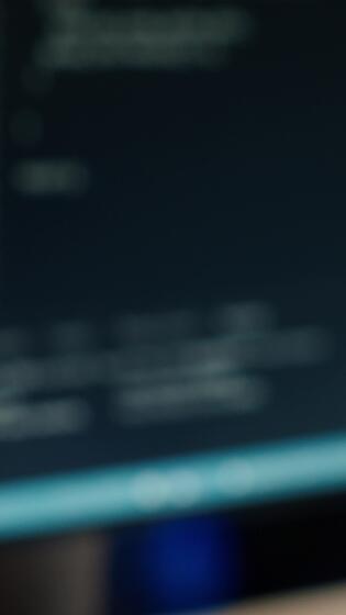 Vertical Extreme close up of software interface on PC screens showing lines of code running in ...