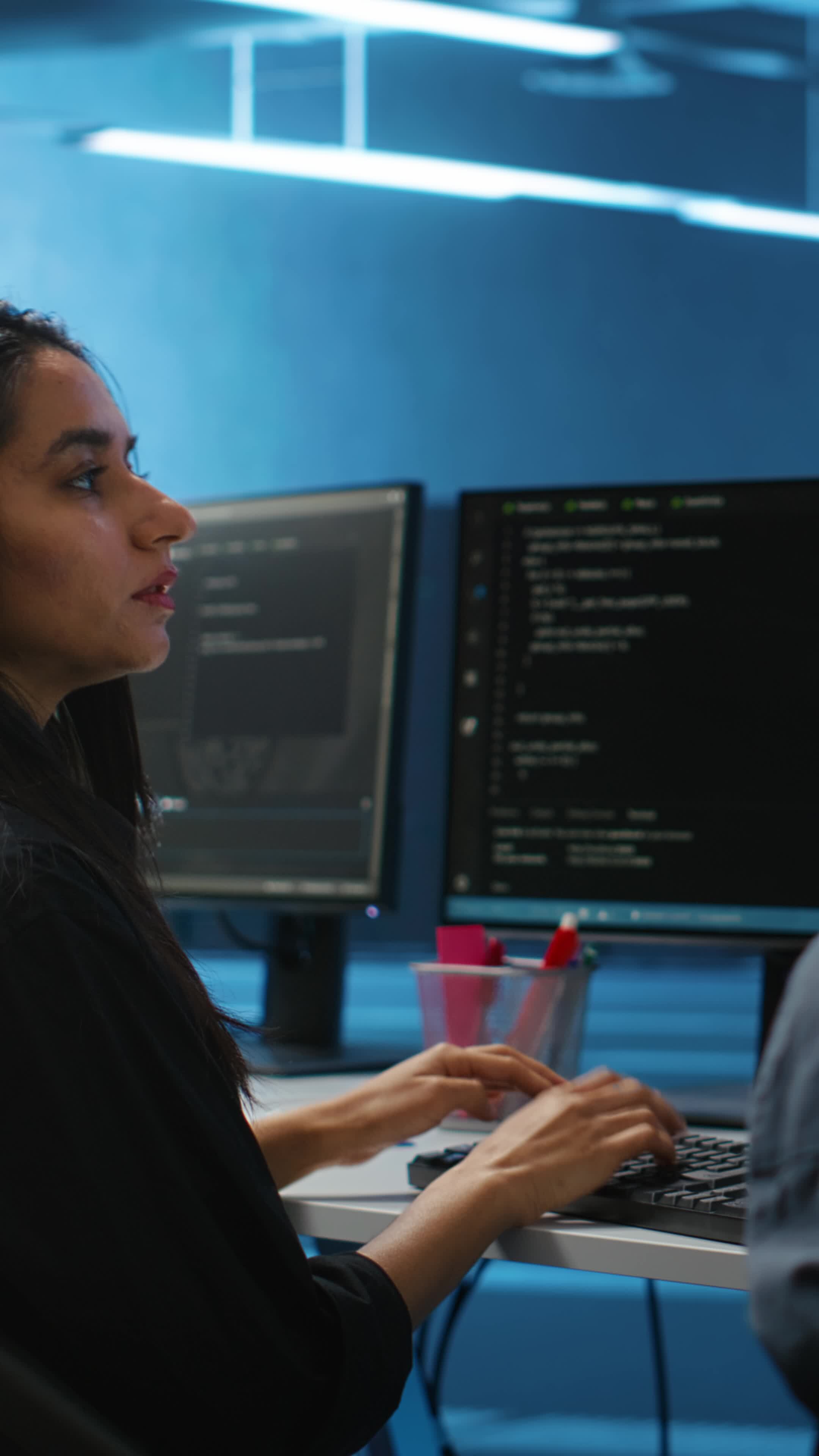 Vertical Multiethnic team of engineers working in high tech server hub, using PCs to analyze ...