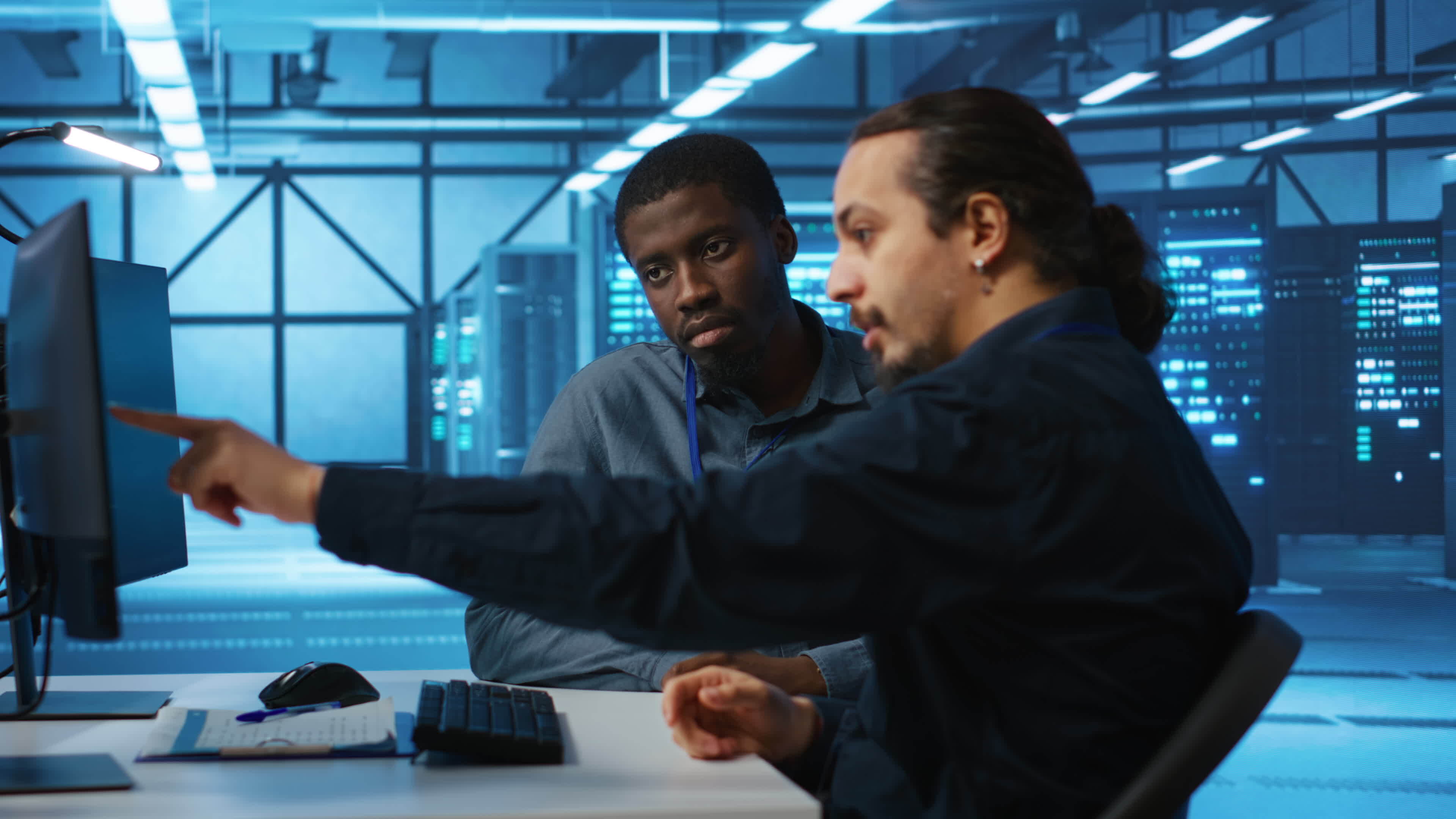 Multiracial engineers programming in high tech facility with server ...