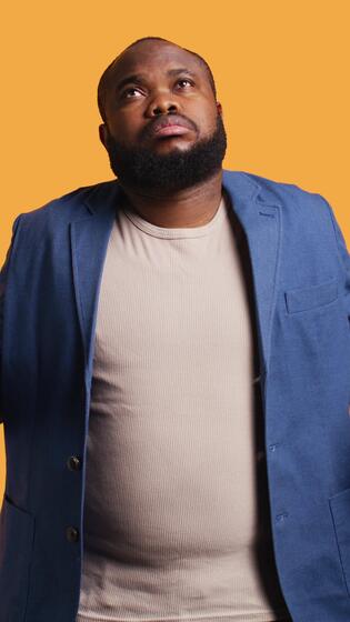 Vertical African american man shrugging shoulders, not caring, having ...