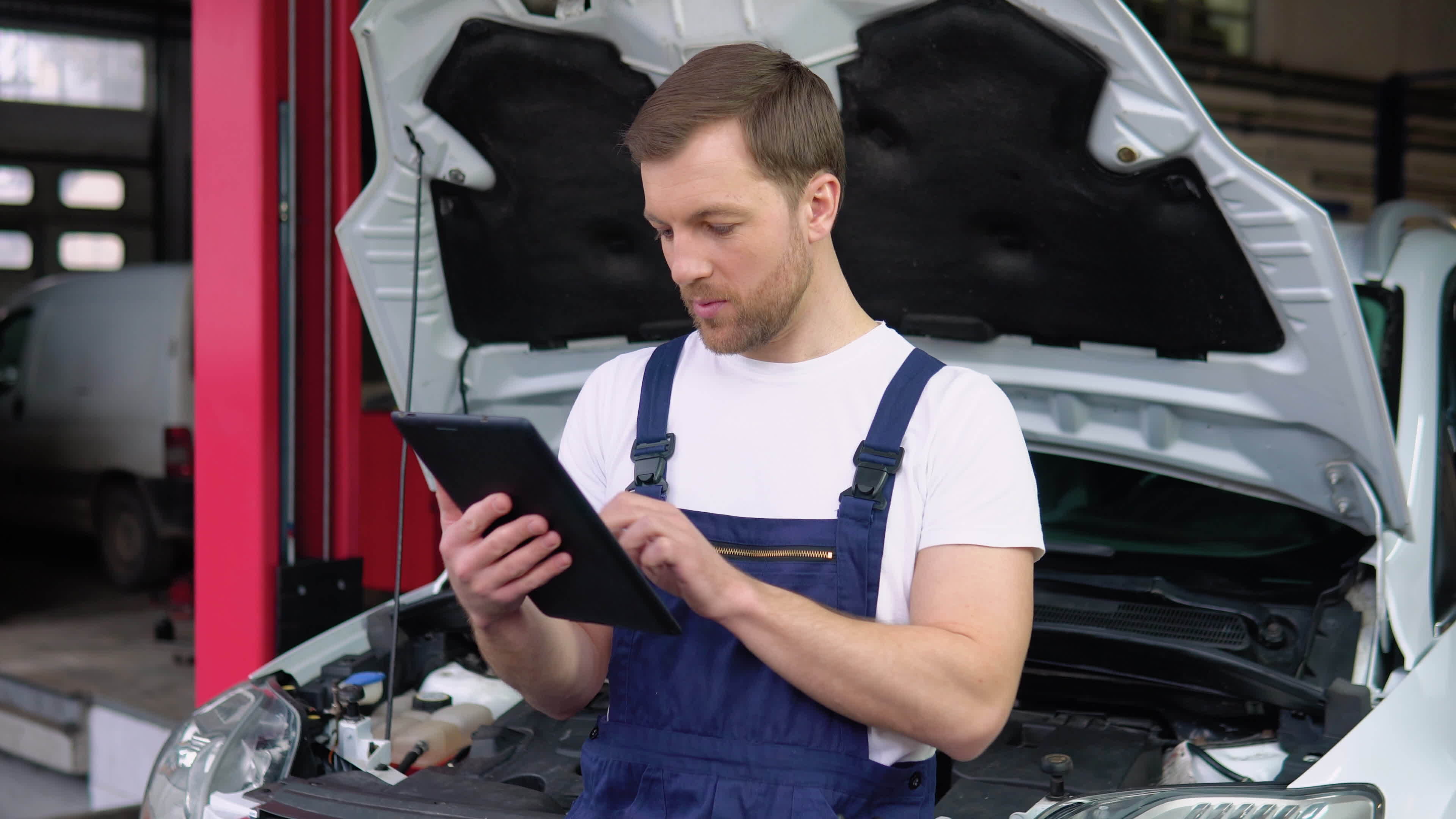 Professional car mechanic working in auto repair service with tablet ...