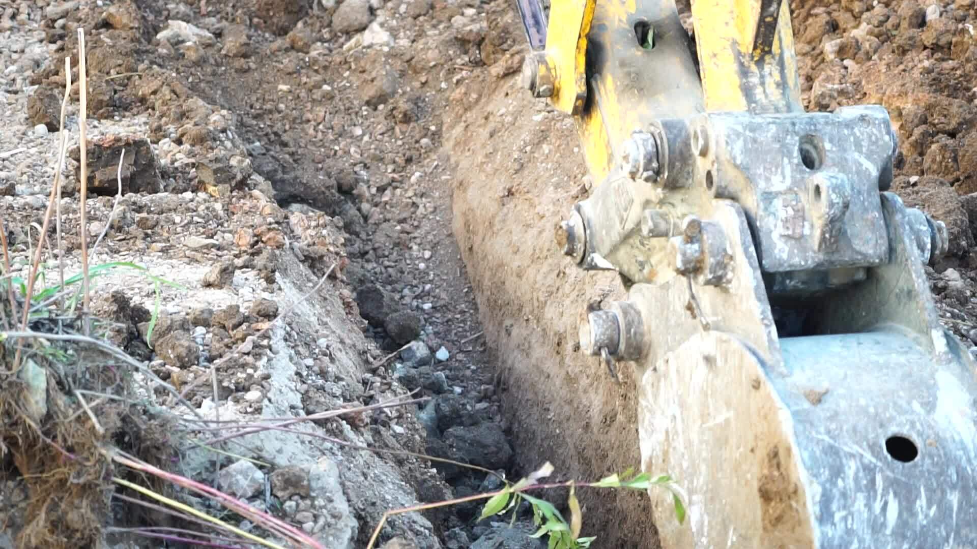 Excavator digs a trench to lay pipes. Close up of an excavator digging ...