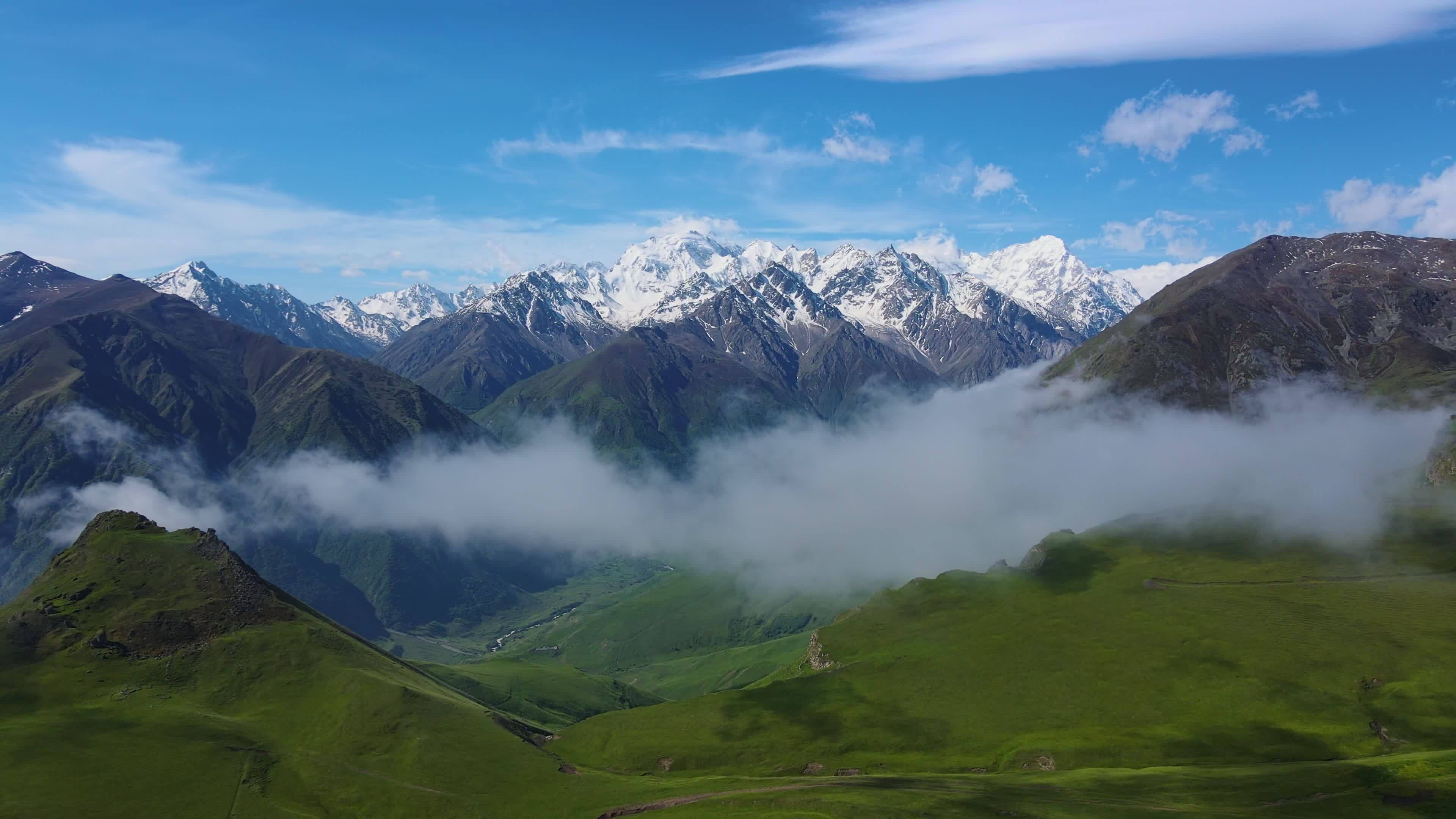 Enjoy the scenic mountain range view with green hills and snowcapped ...