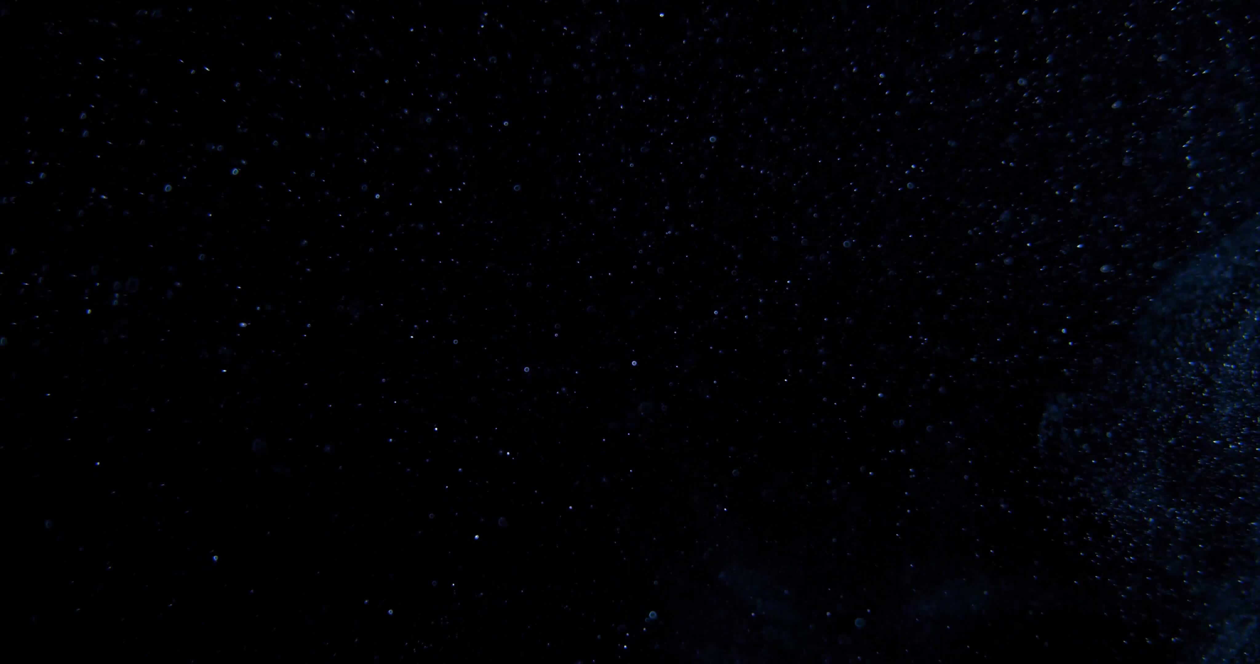 Cinematic dust particles floating on Black Screen Overlay. RED camera footage in slow motion ...