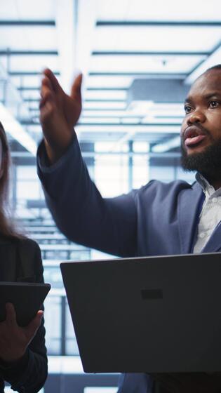 Vertical System Administrators In Data Center Overseeing Server Operations Using Notebook And