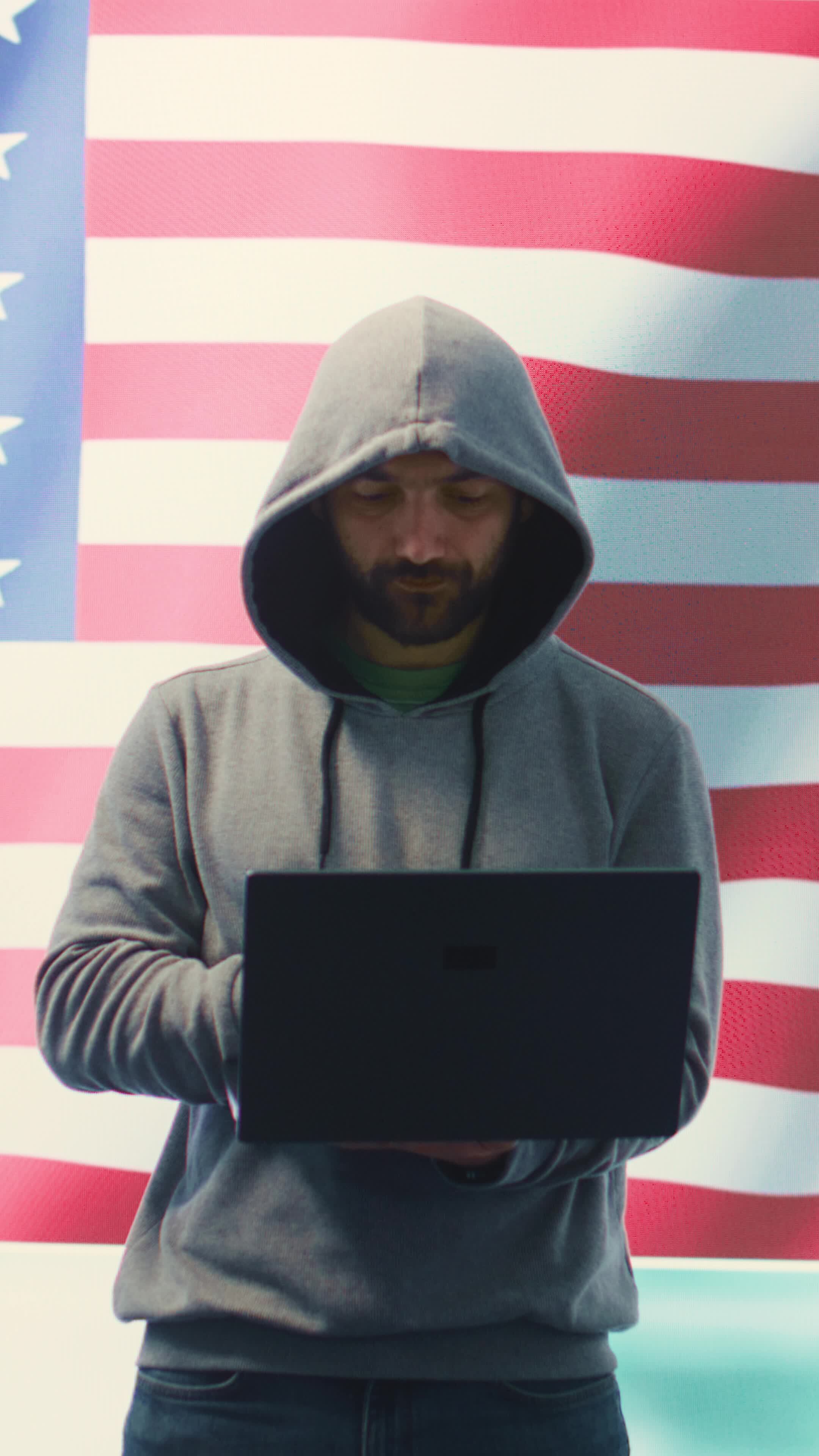 Vertical A Hacker Working In A Governmental It Workspace With The Usa Flag Running On Big Screen